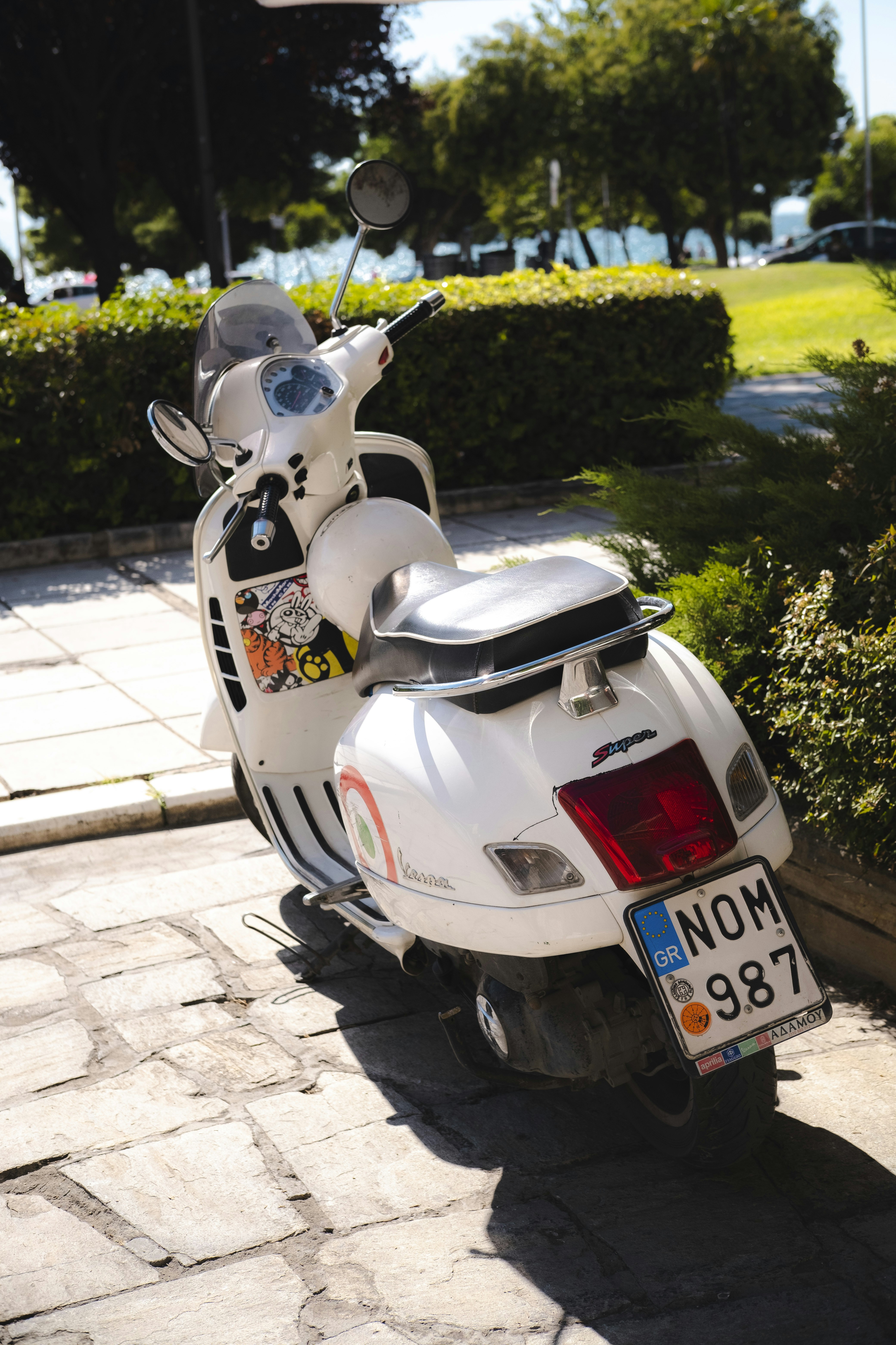 Sunlit Vespa Portrait: chrome reflections and stickered panels in a tranquil courtyard