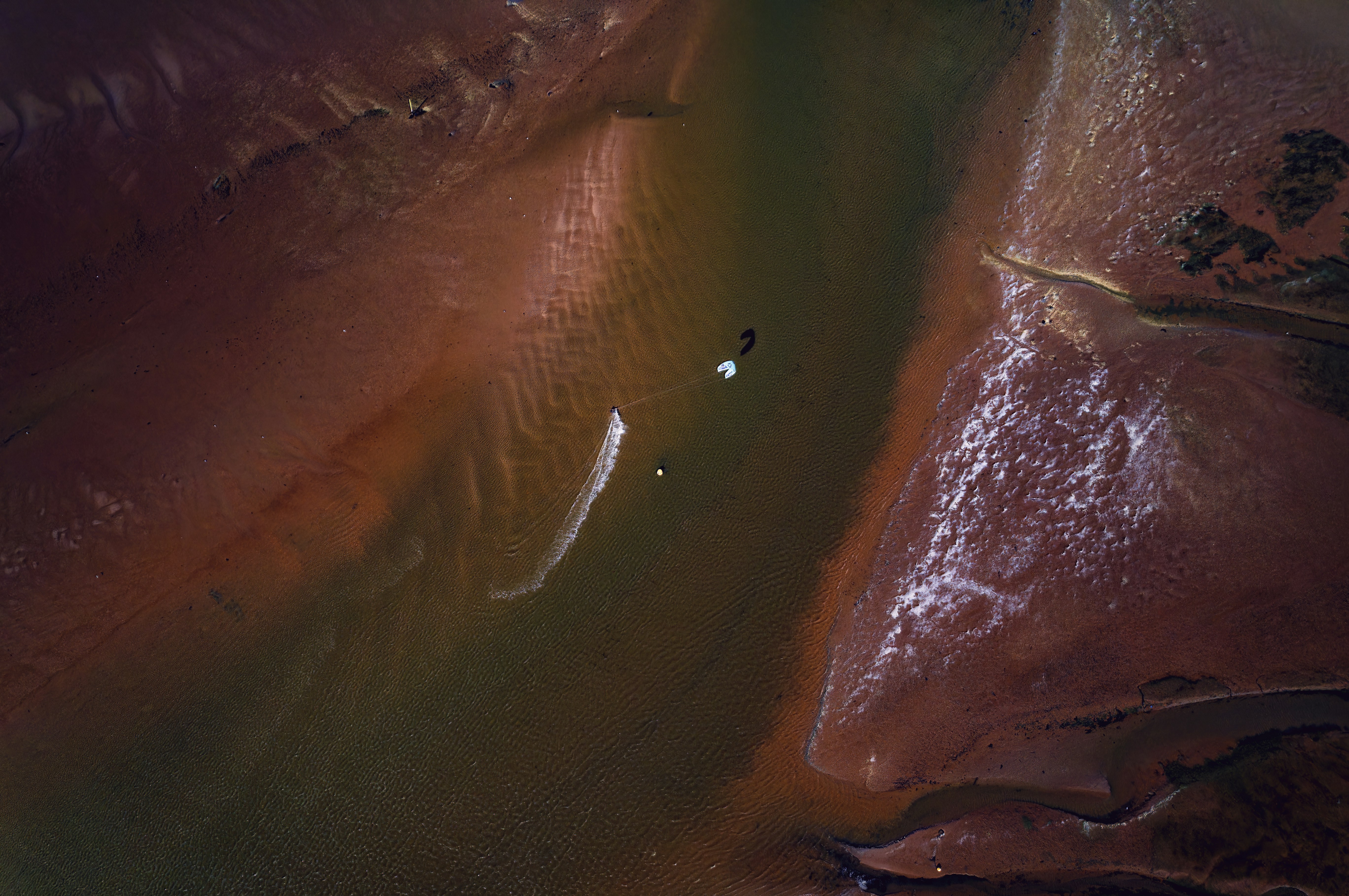 Emerald River Winding Through a Rust-Red Canyon, with Two White Dots Adrift