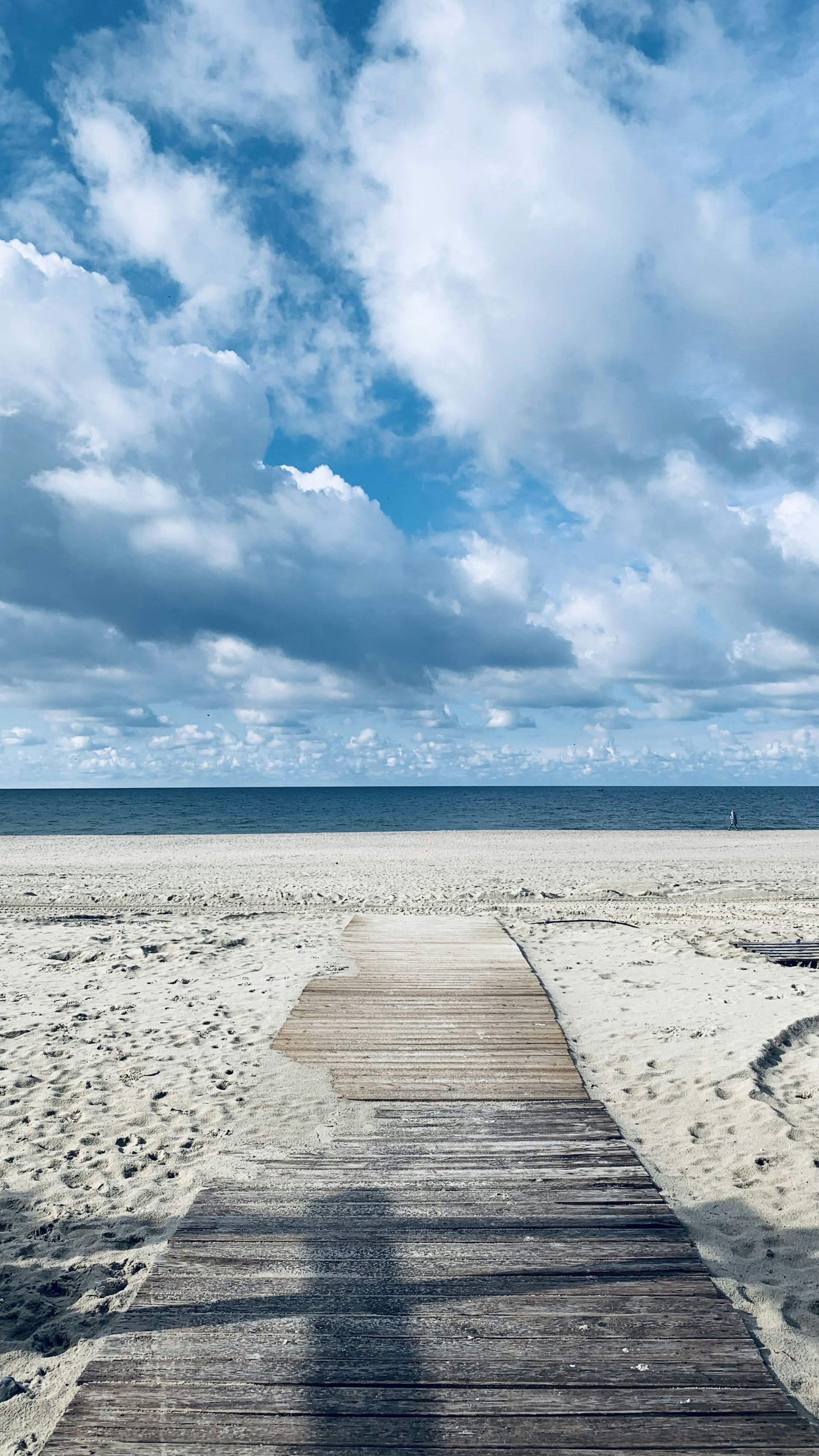 A wooden walkway leading to the ocean under a cloudy blue sky photo ...