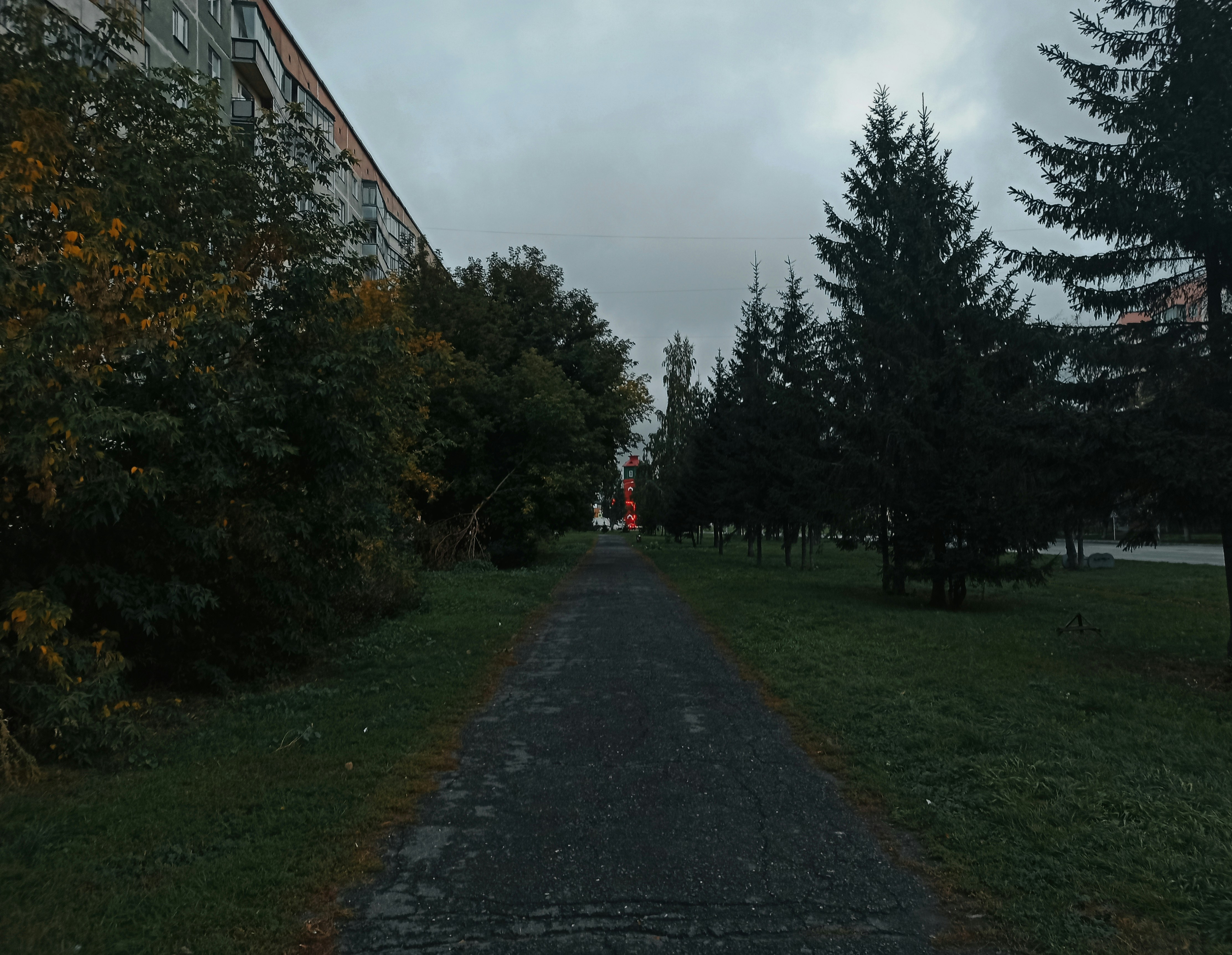Red beacon on a damp park path under gray skies