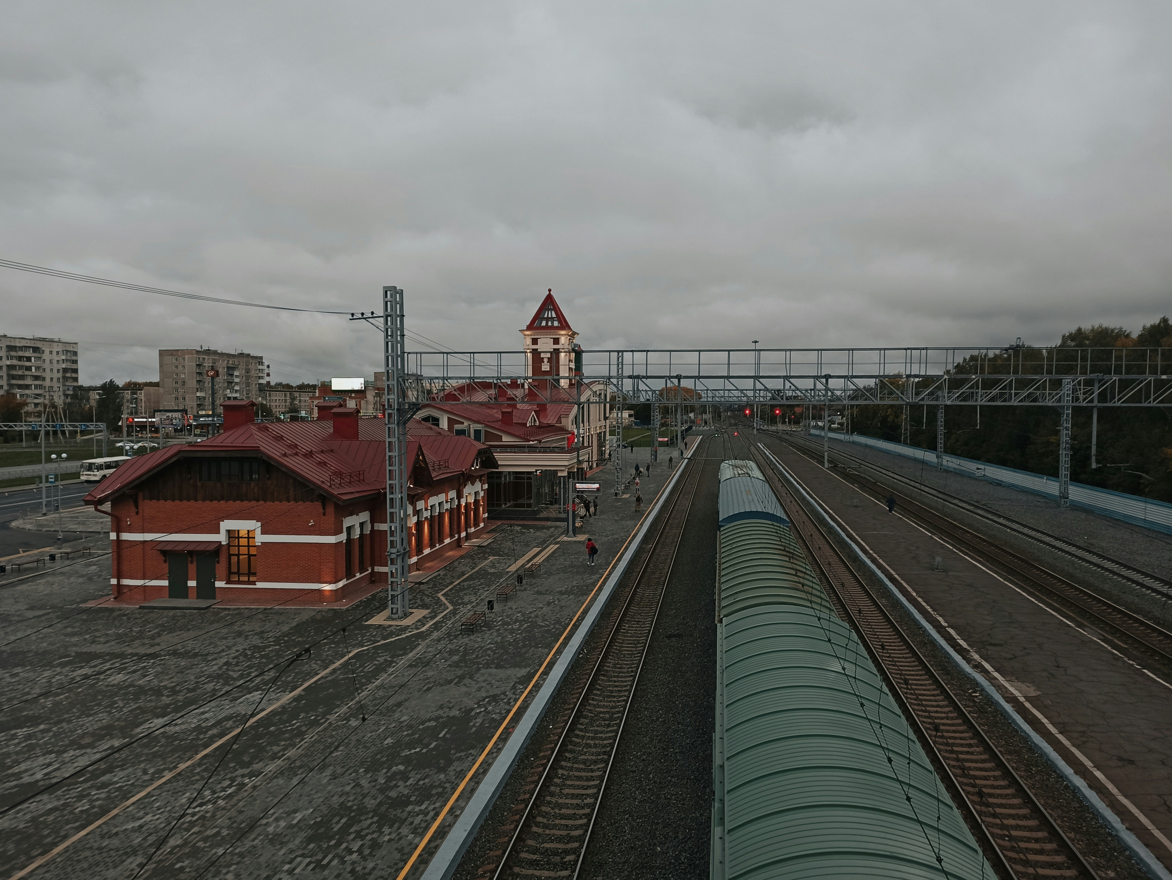 Convergence at the Red Brick Station: Rails Lead to a Clock Tower Under Overcast Skies