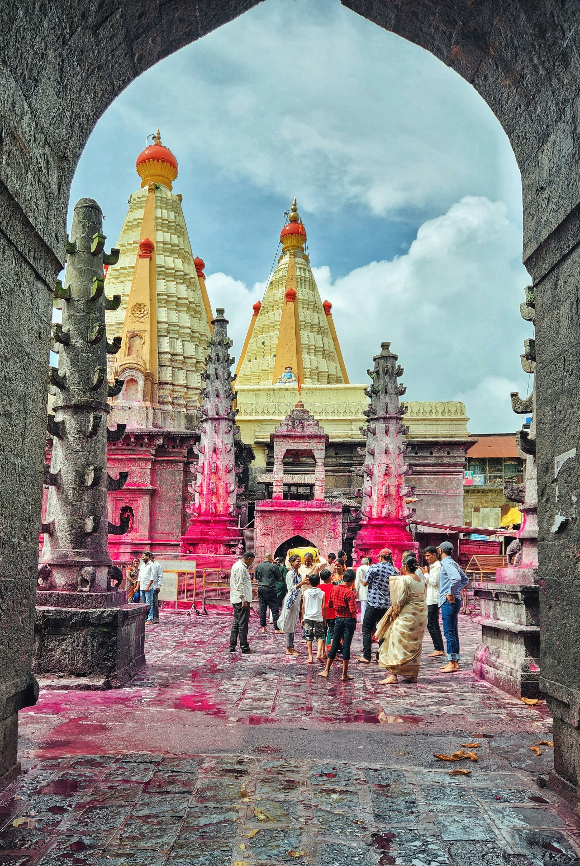 Colorful temple scene bustling with visitors amidst intricate architecture and festive decorations. The atmosphere is filled with cultural significance and communal joy.