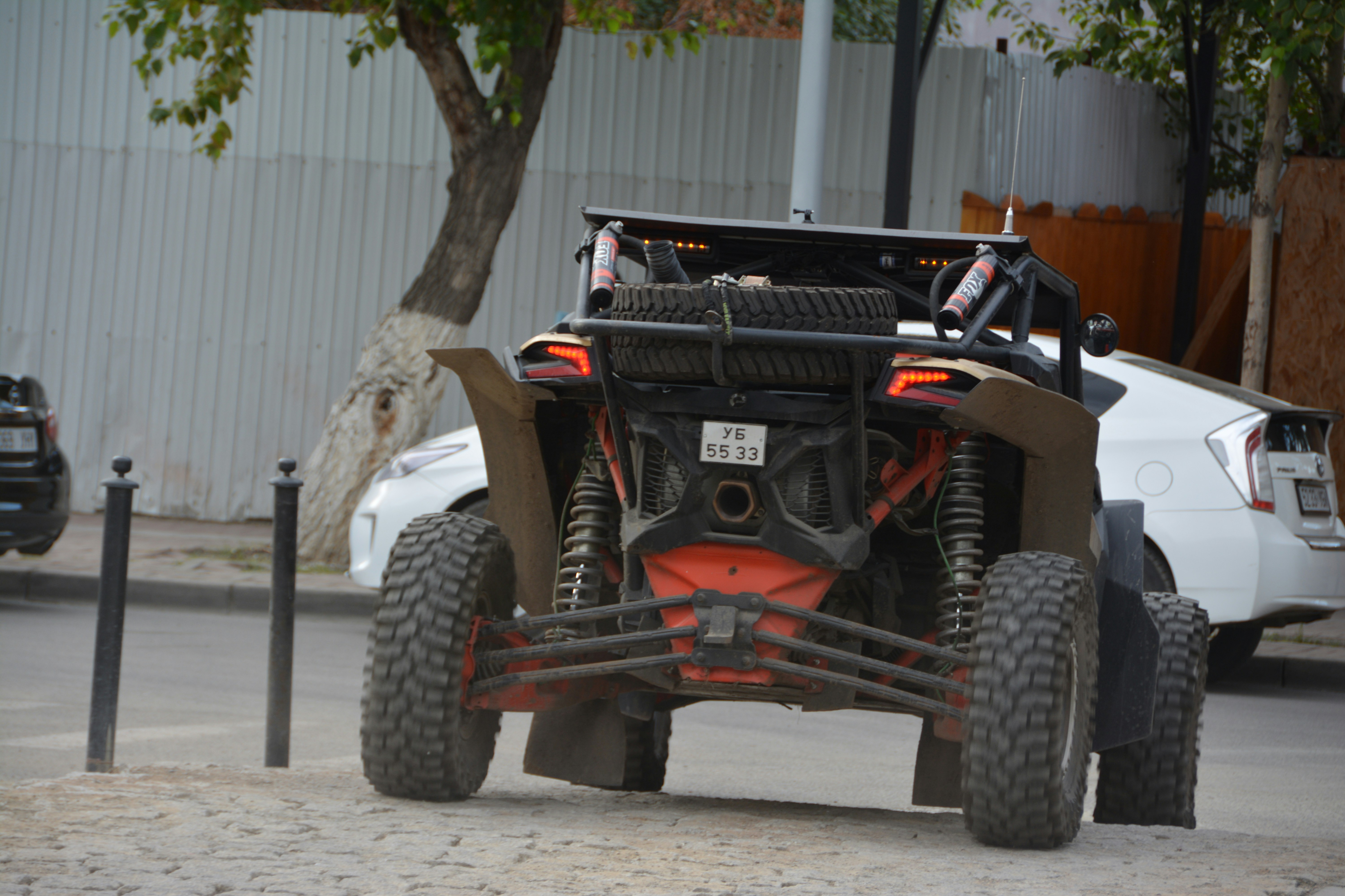 Four-wheeler navigating an urban street with trees and parked cars.