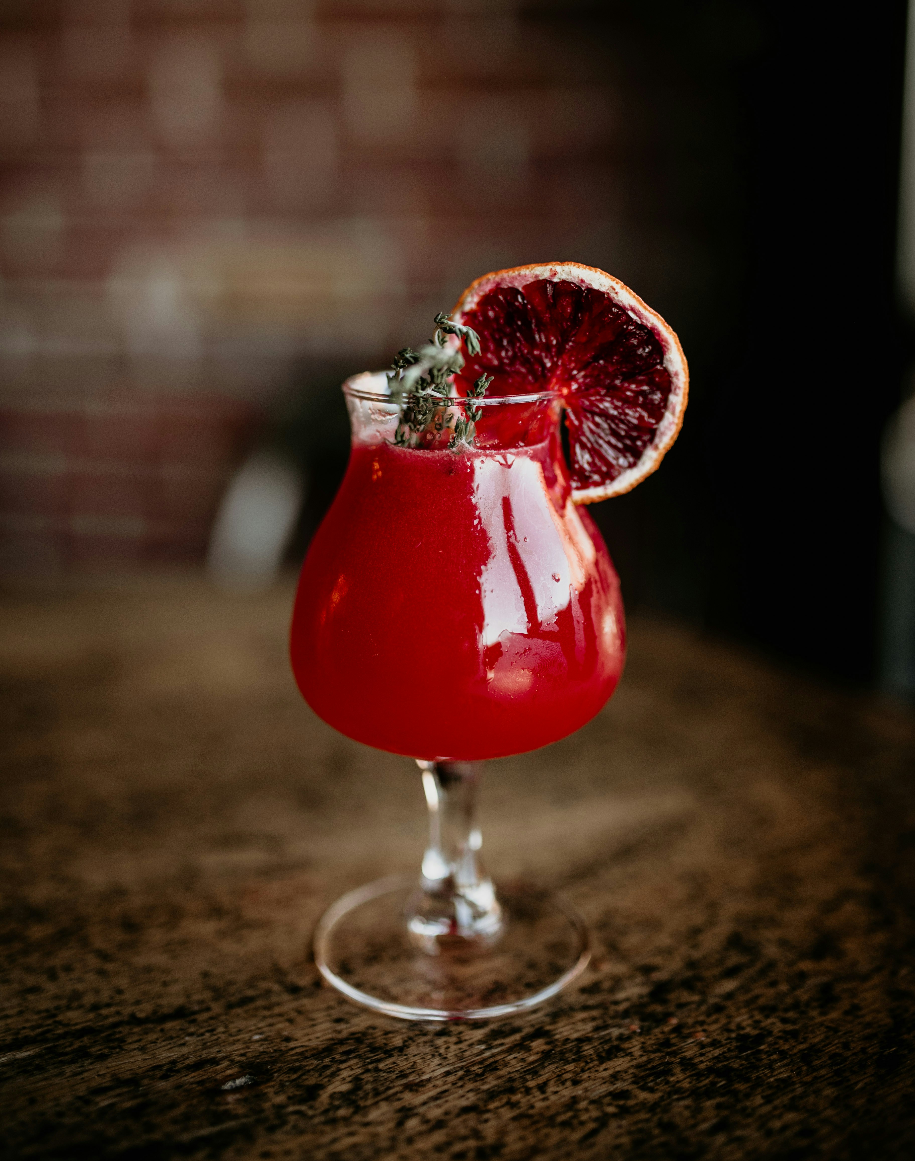 A red drink with a slice of grape on top of it photo – Free Beverage ...