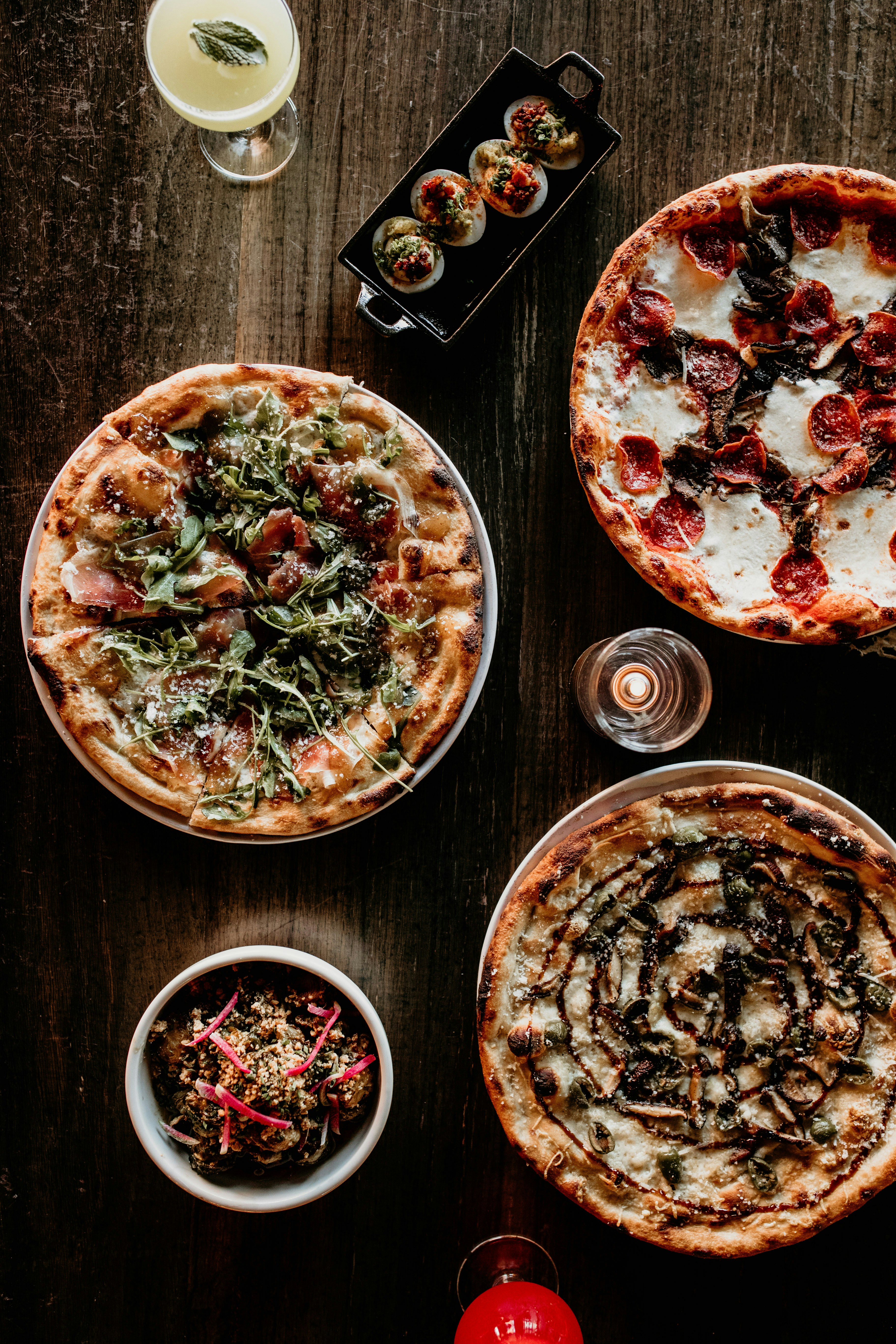 A table topped with two pizzas covered in toppings photo – Free ...