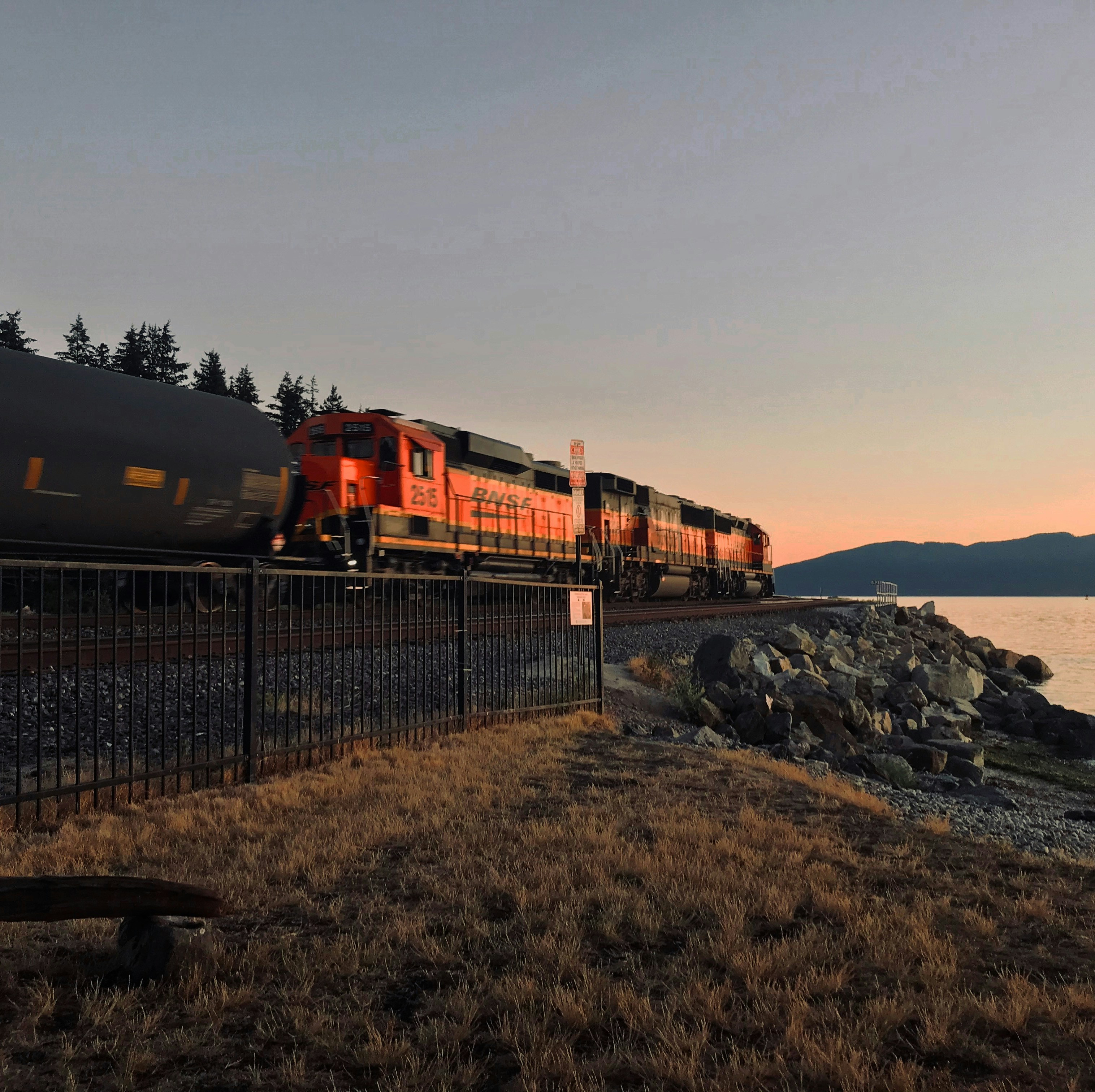 Dusk on the Rails: Red Freight Engine Crossing the Shoreline