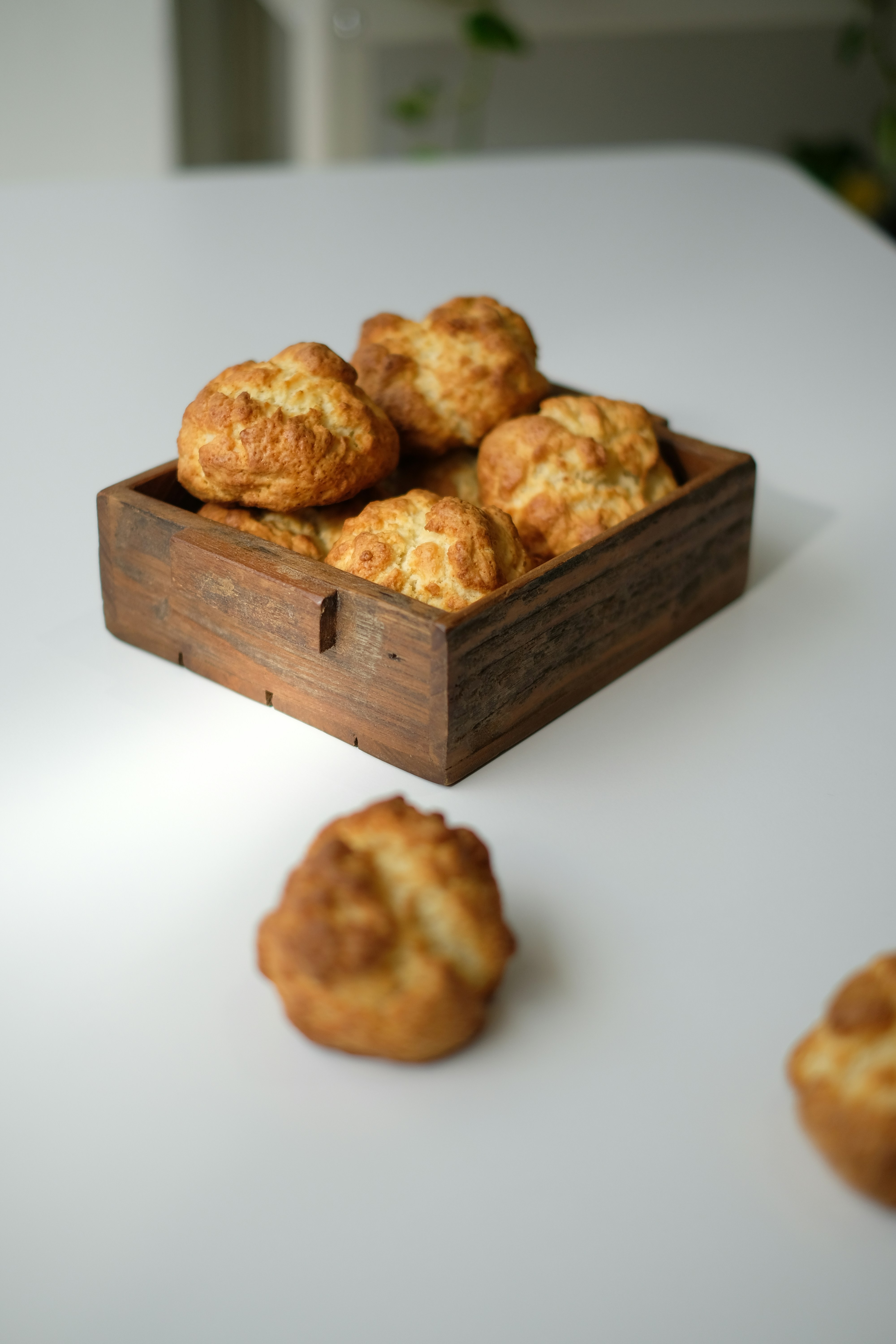 Sunlit Rustic Muffins in a Weathered Wooden Box on a White Surface