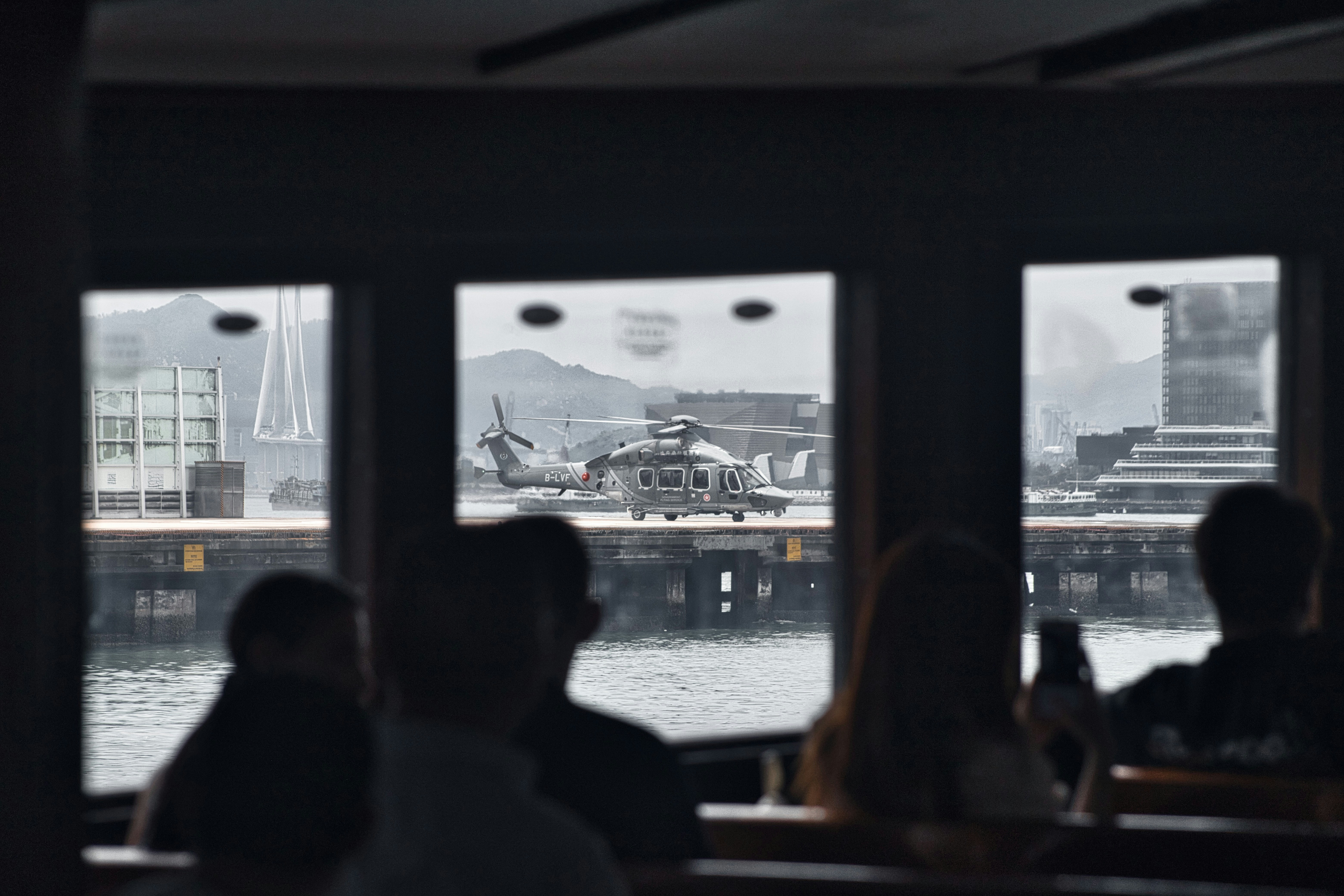 Through the Glass: a Dockside Helicopter Framed by Quiet Passengers