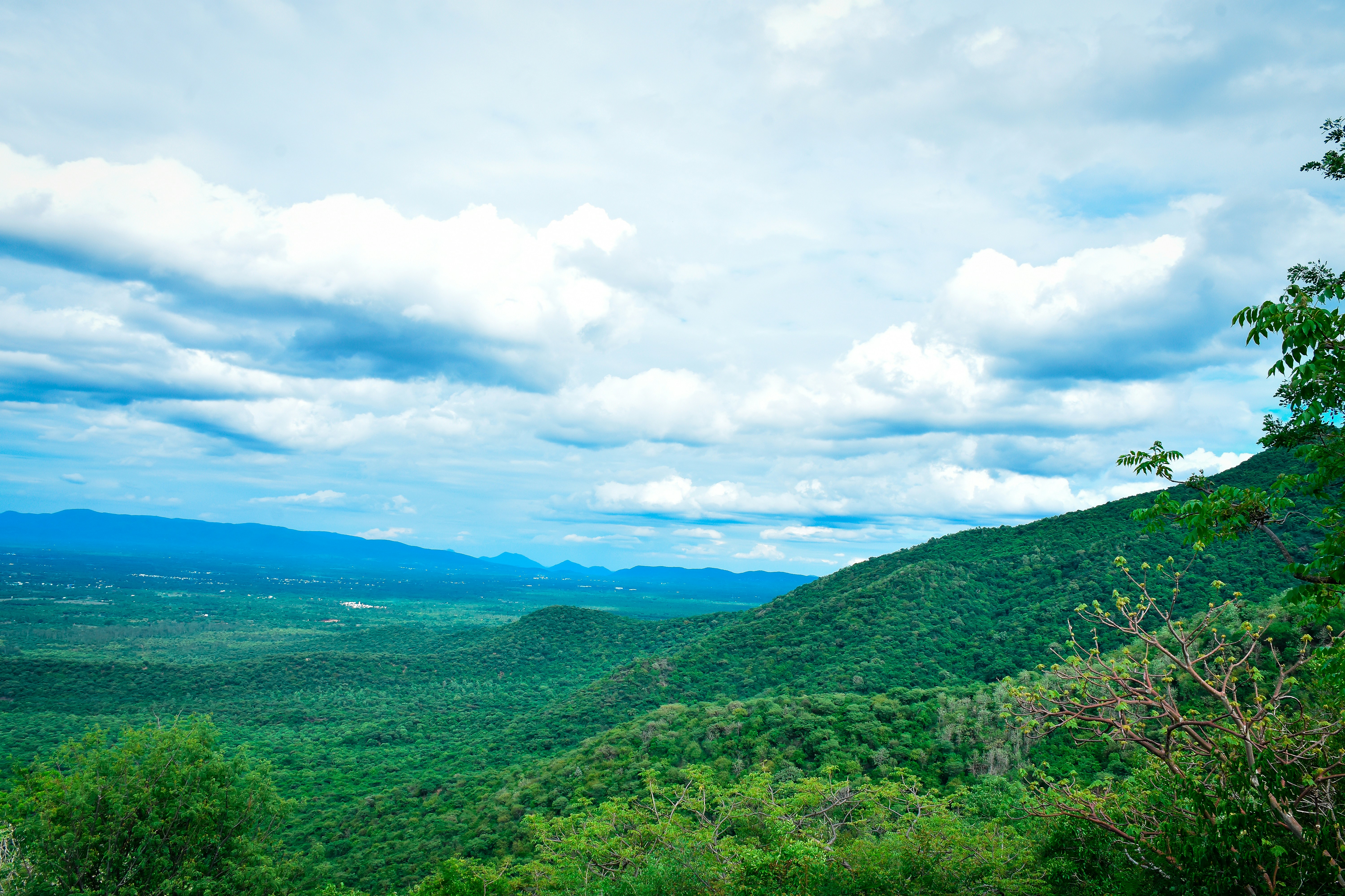 Lush green hills stretch beneath a vast, cloud-dappled sky.