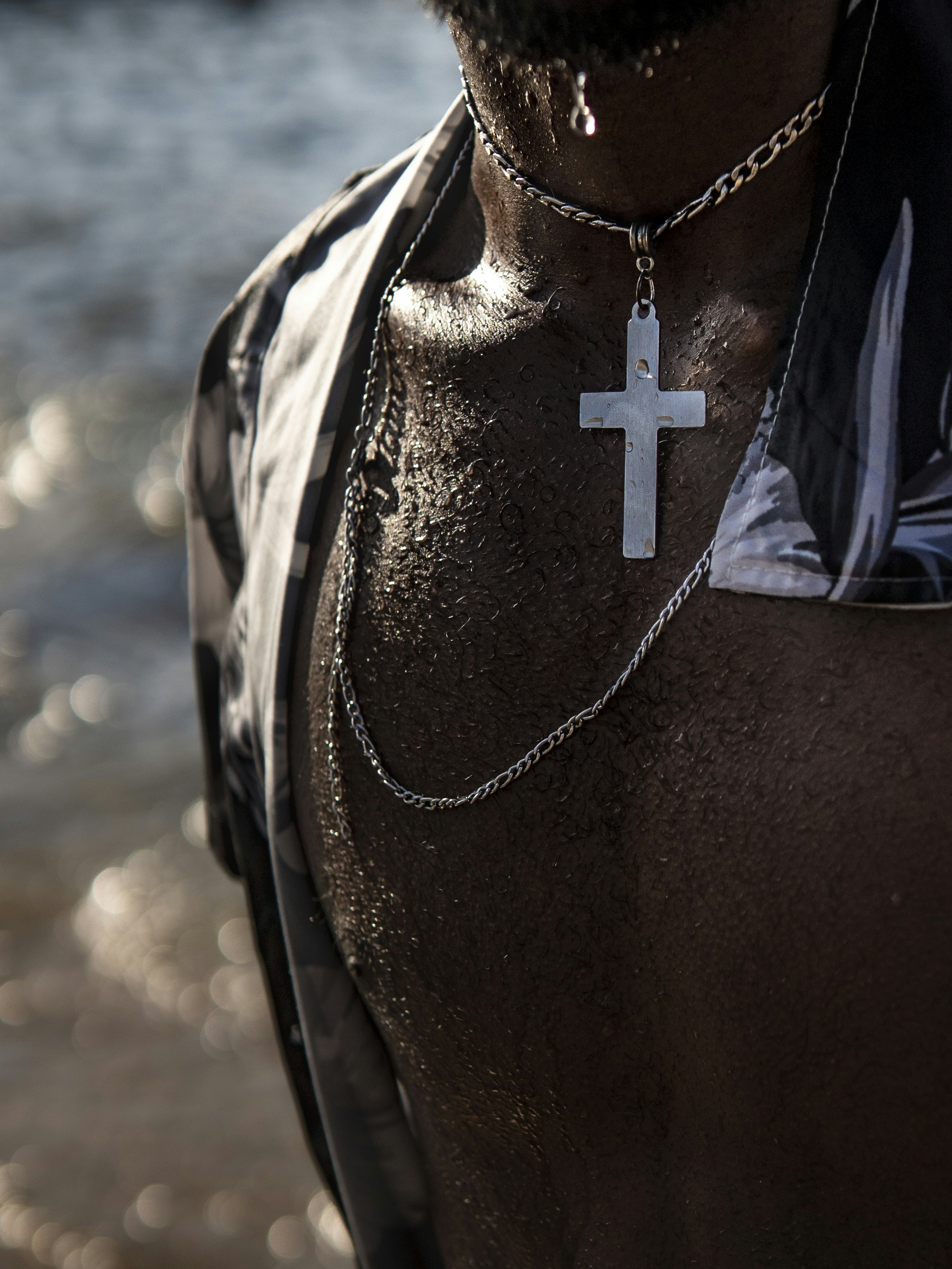 Cross Pendant in Sea-Burnished Light: A Close-Up of Wet Skin and Chains
