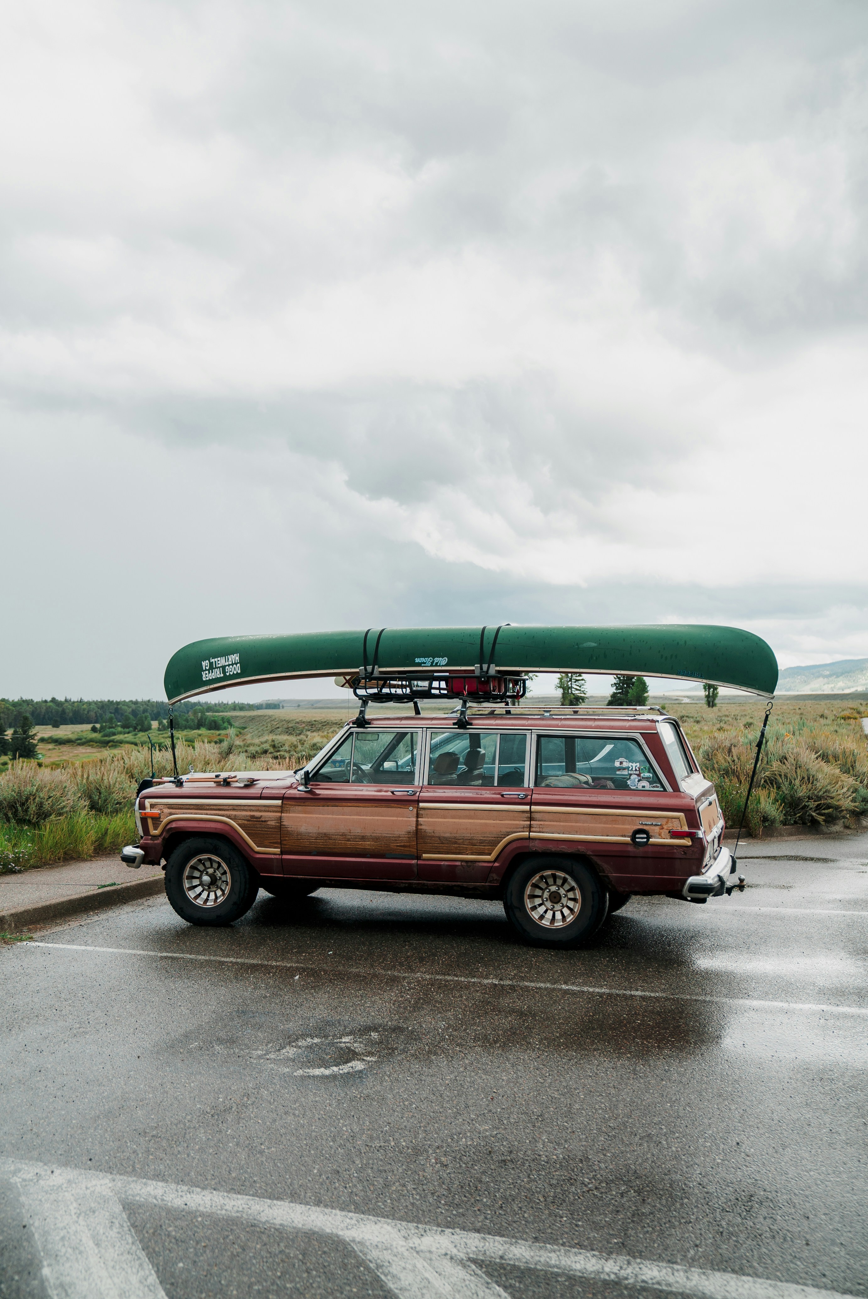 Canoe-Top Adventure: A Weathered SUV on a Rainy Prairie Road
