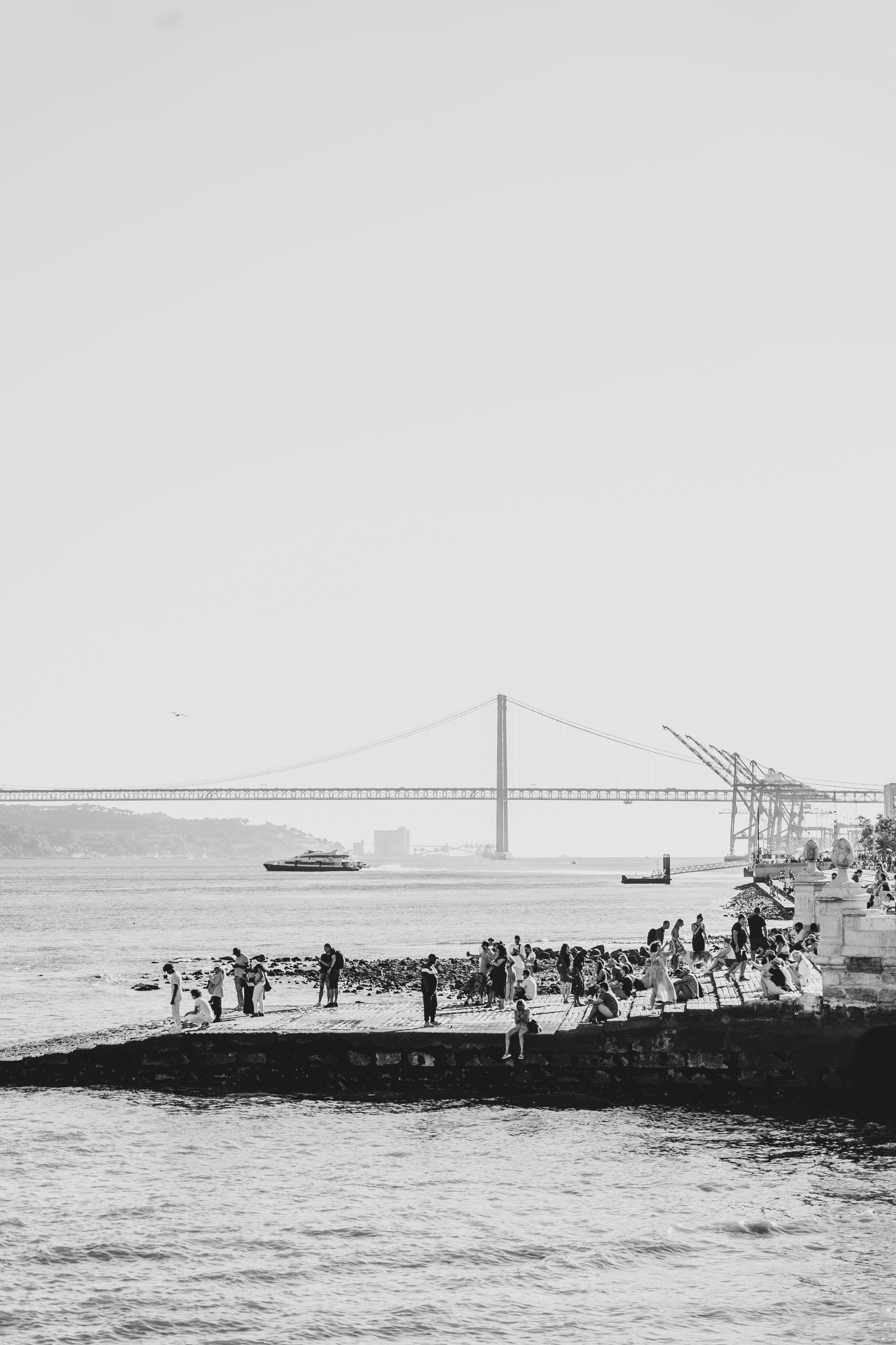 Crowded Jetty Under a Distant Suspension Bridge