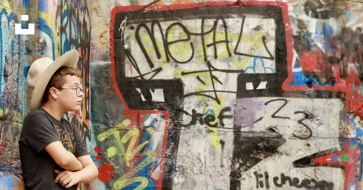 Un Jeune Garçon Debout Devant Un Mur Couvert De Graffitis Photo Photo