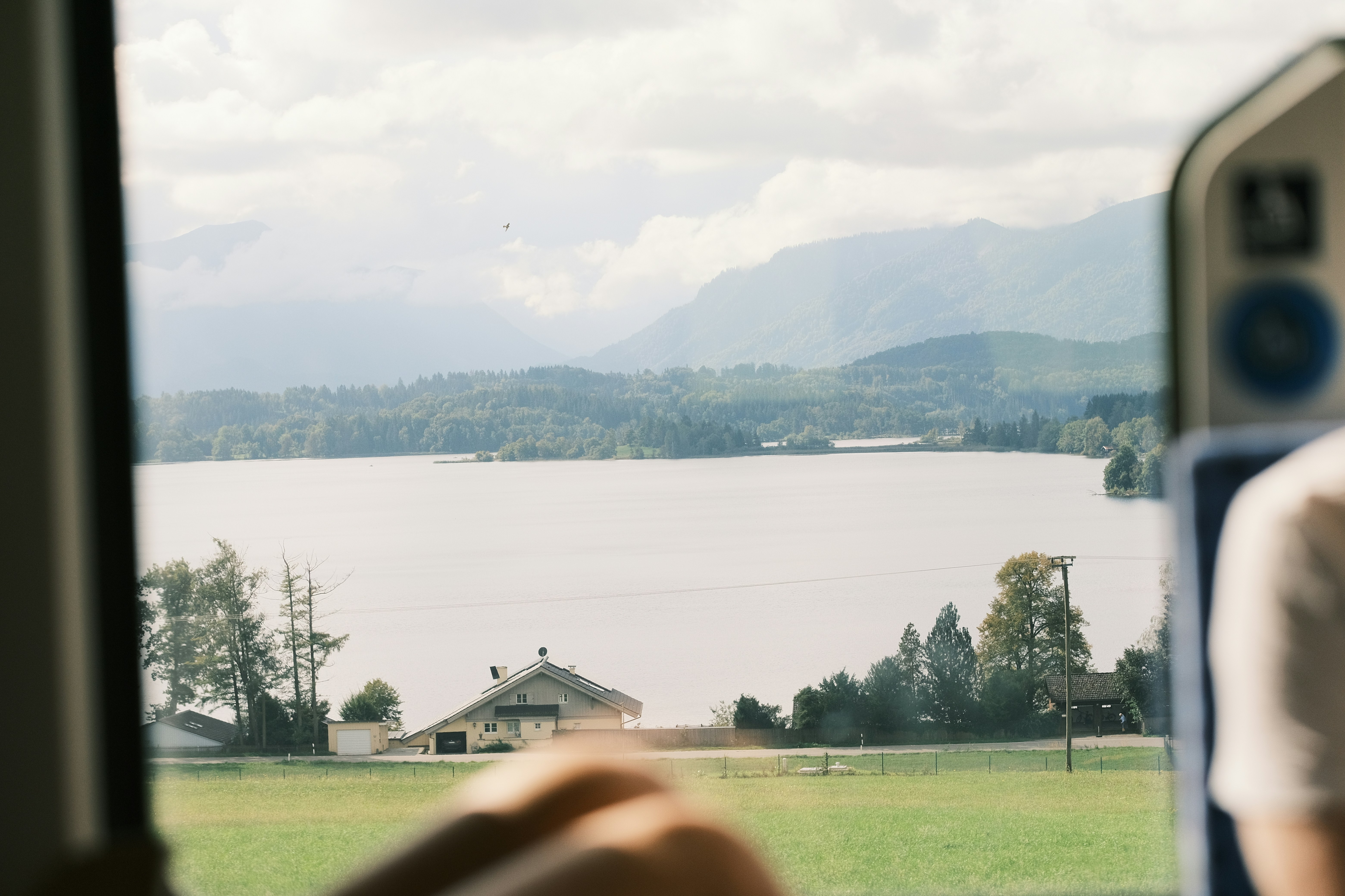a person looking out of a train window at a lake