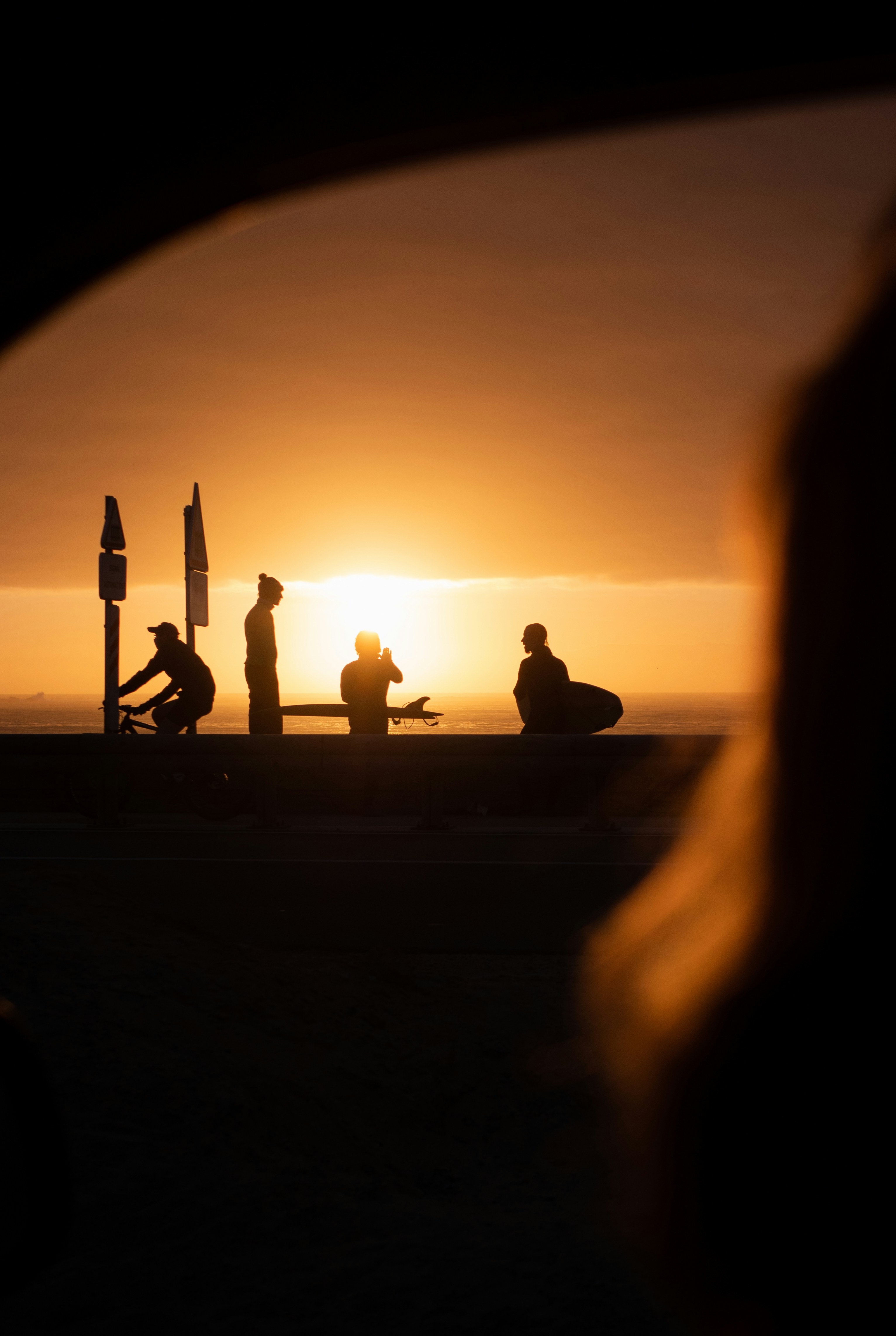 Sunset Silhouettes on the Seawall: Surfers and Spectator at Golden Hour