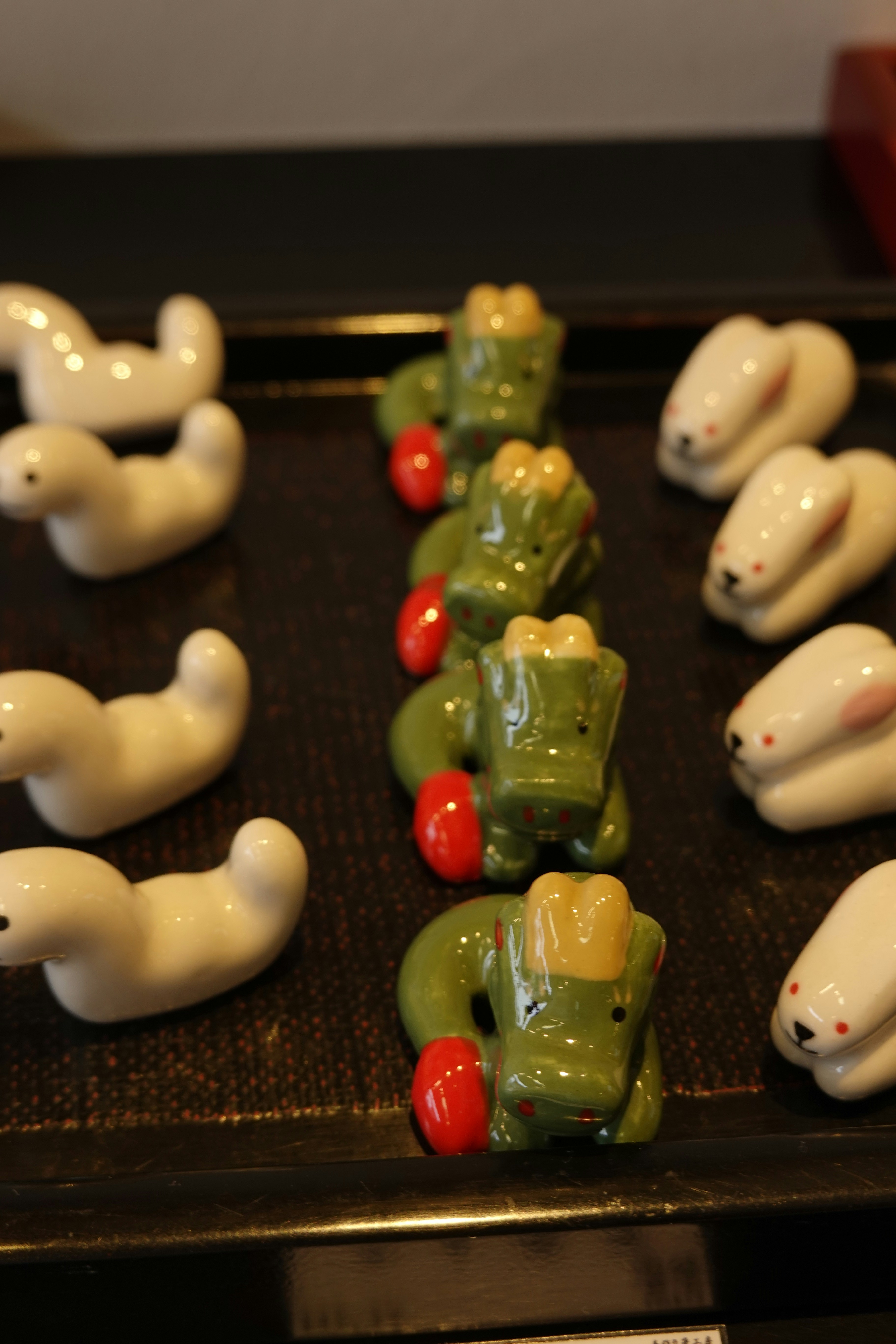 Ceramic Frog Lineup on a Glossy Tray, Flanked by White Rabbit Figurines