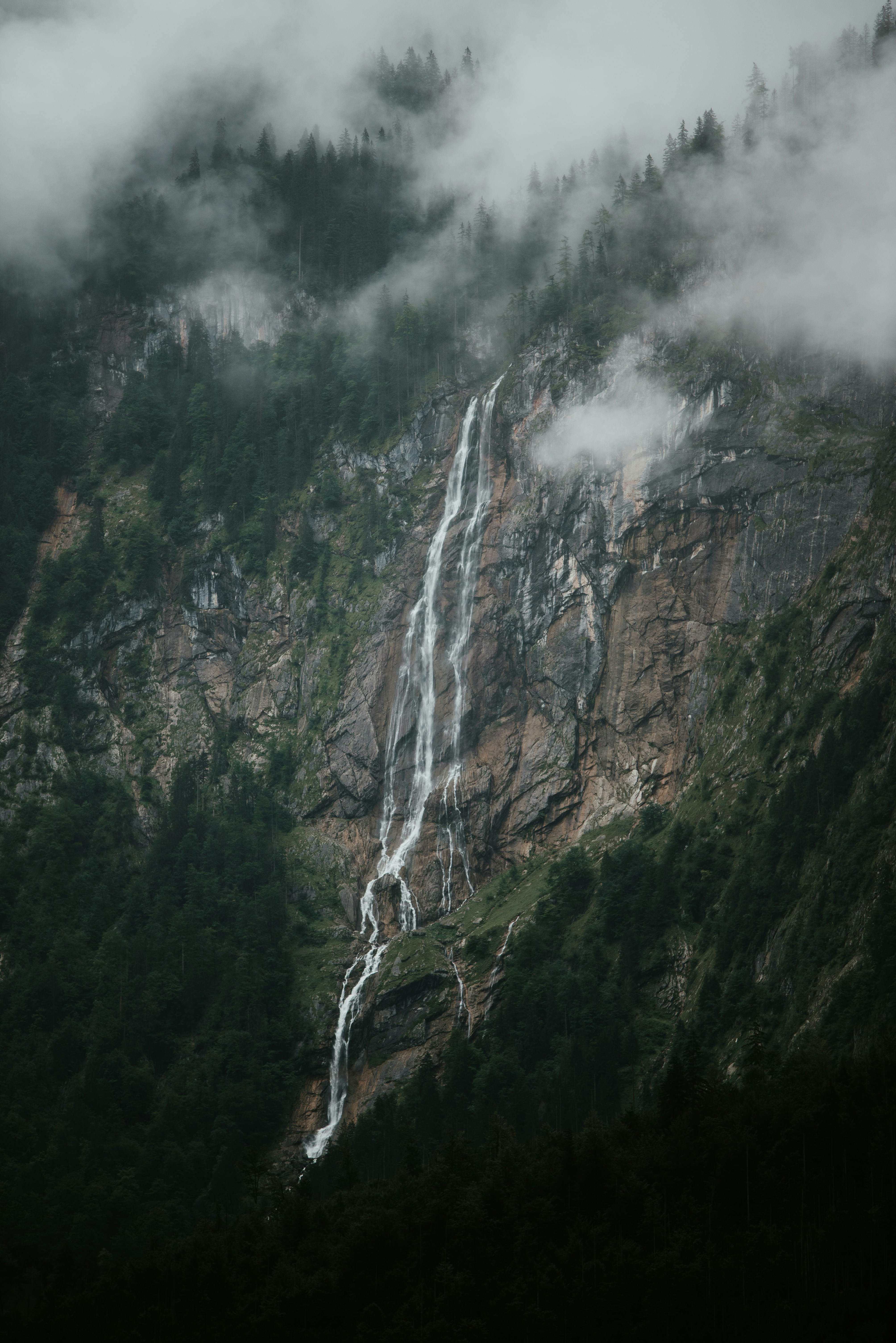 A very tall waterfall in the middle of a forest photo – Free ...