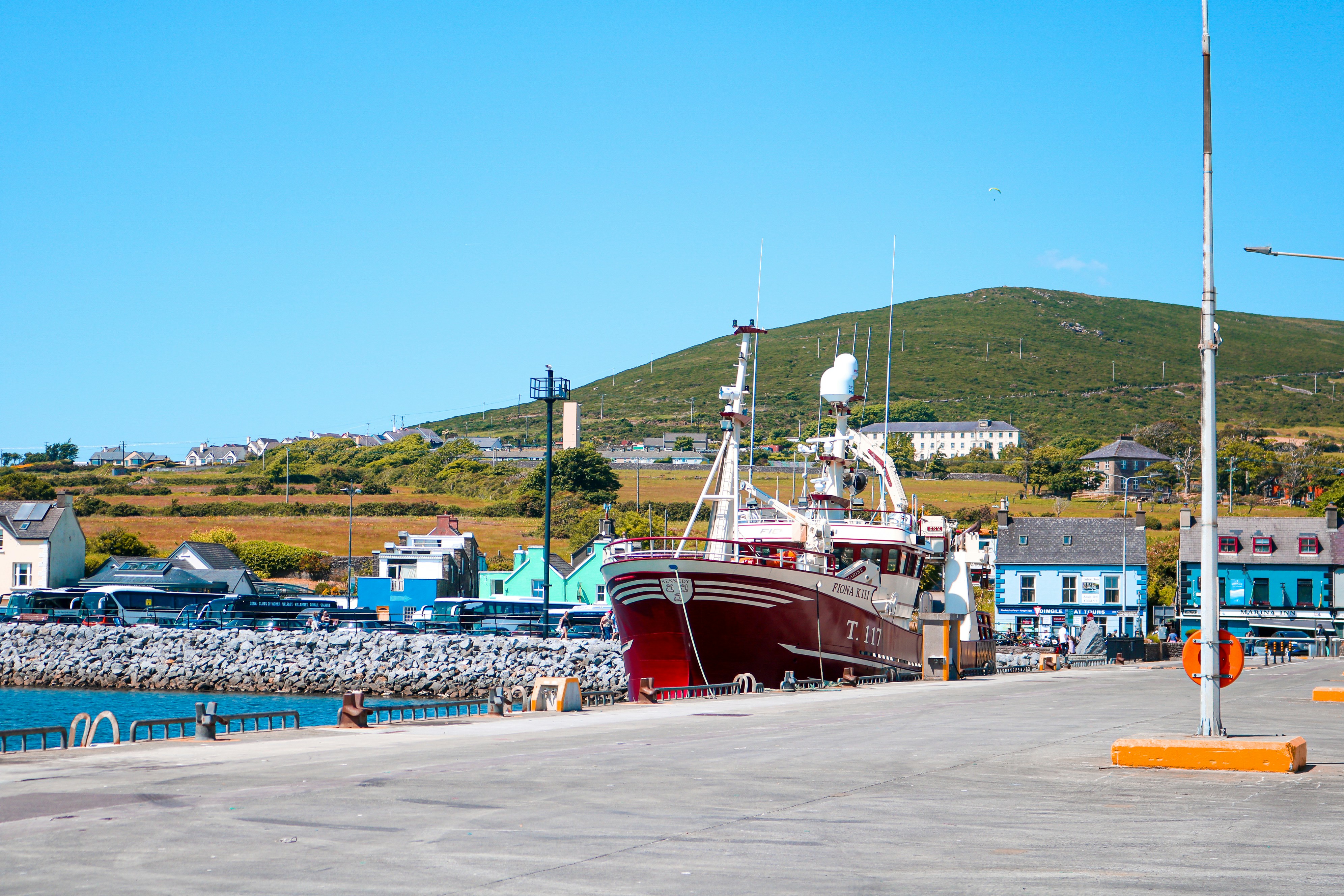 A boat docked in a harbor next to a hill photo – Free Dingle harbour ...