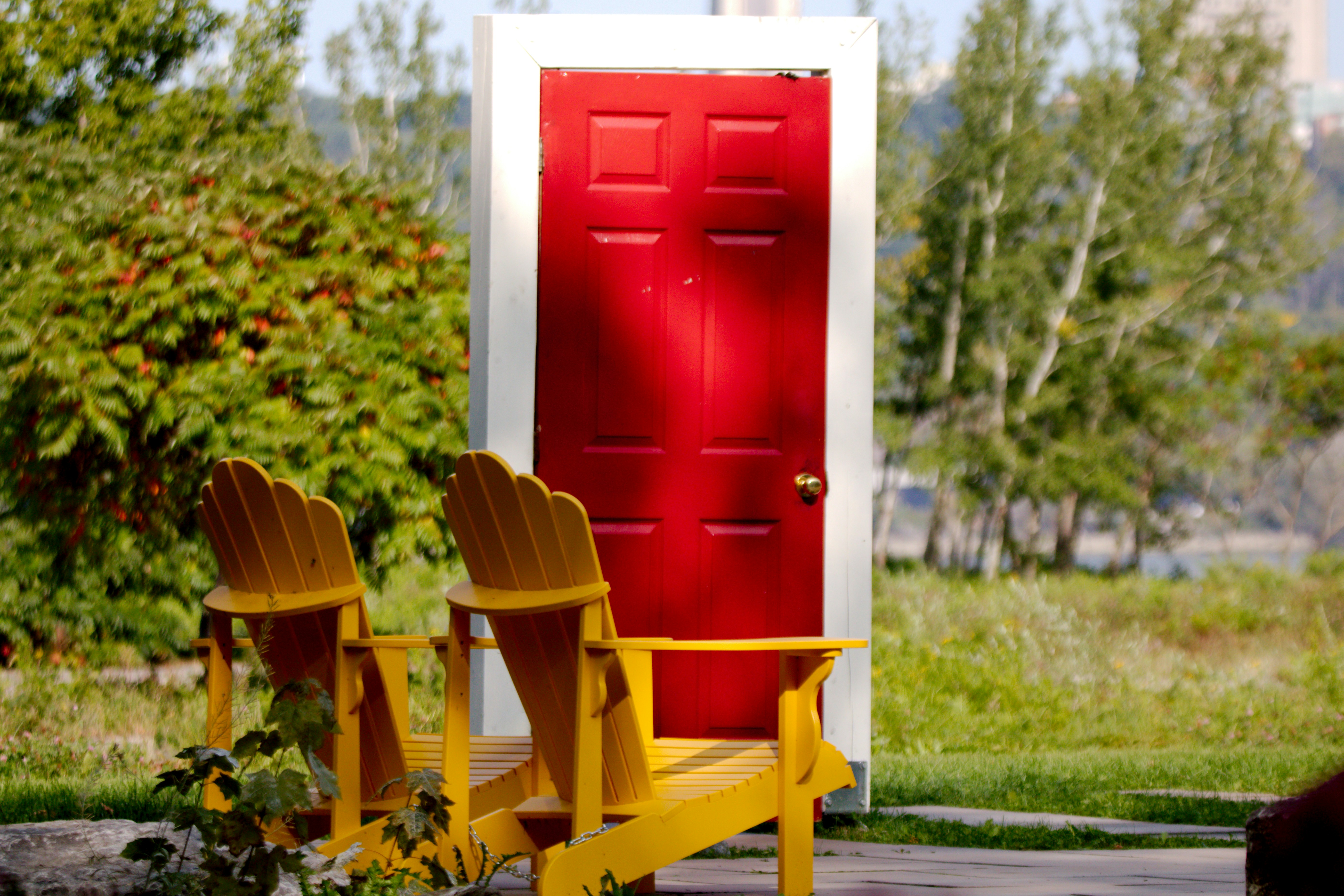 The Red Door Stage: Two Yellow Chairs in a Sunlit Park