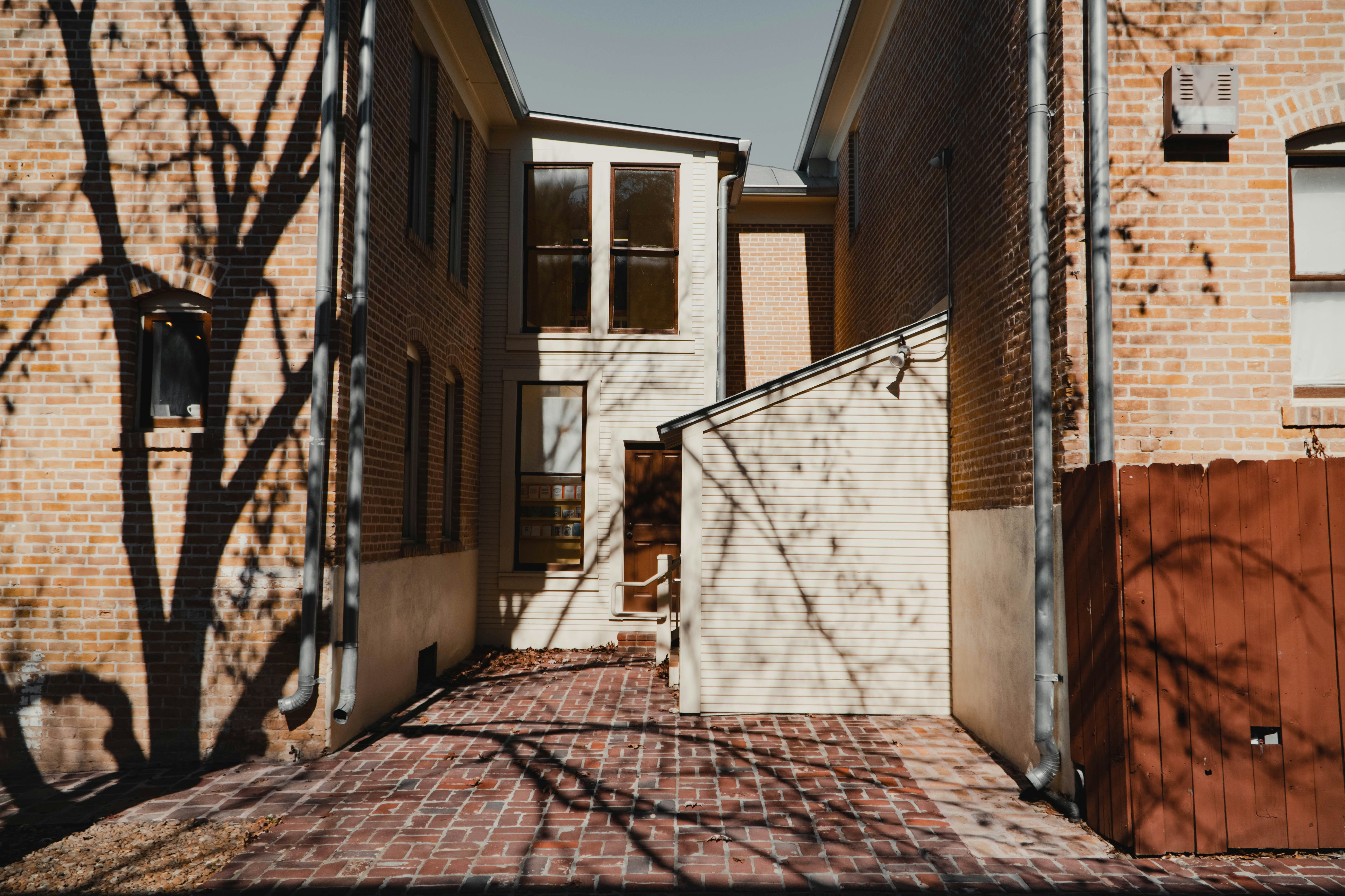 A narrow alley way with brick buildings and trees photo – Free San ...