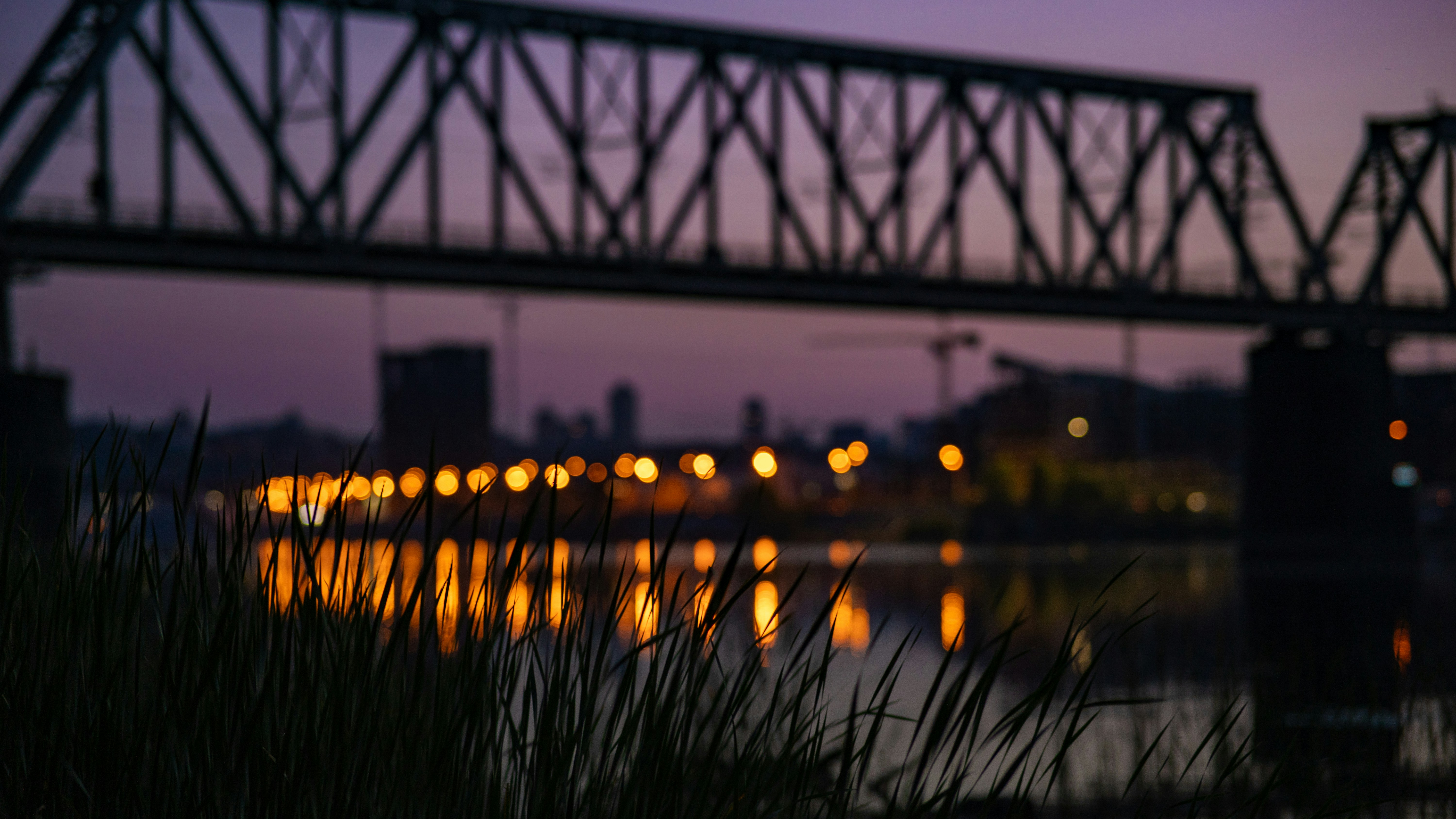 Dusk Across the River: Golden Orbs Reflected Under a Truss Bridge