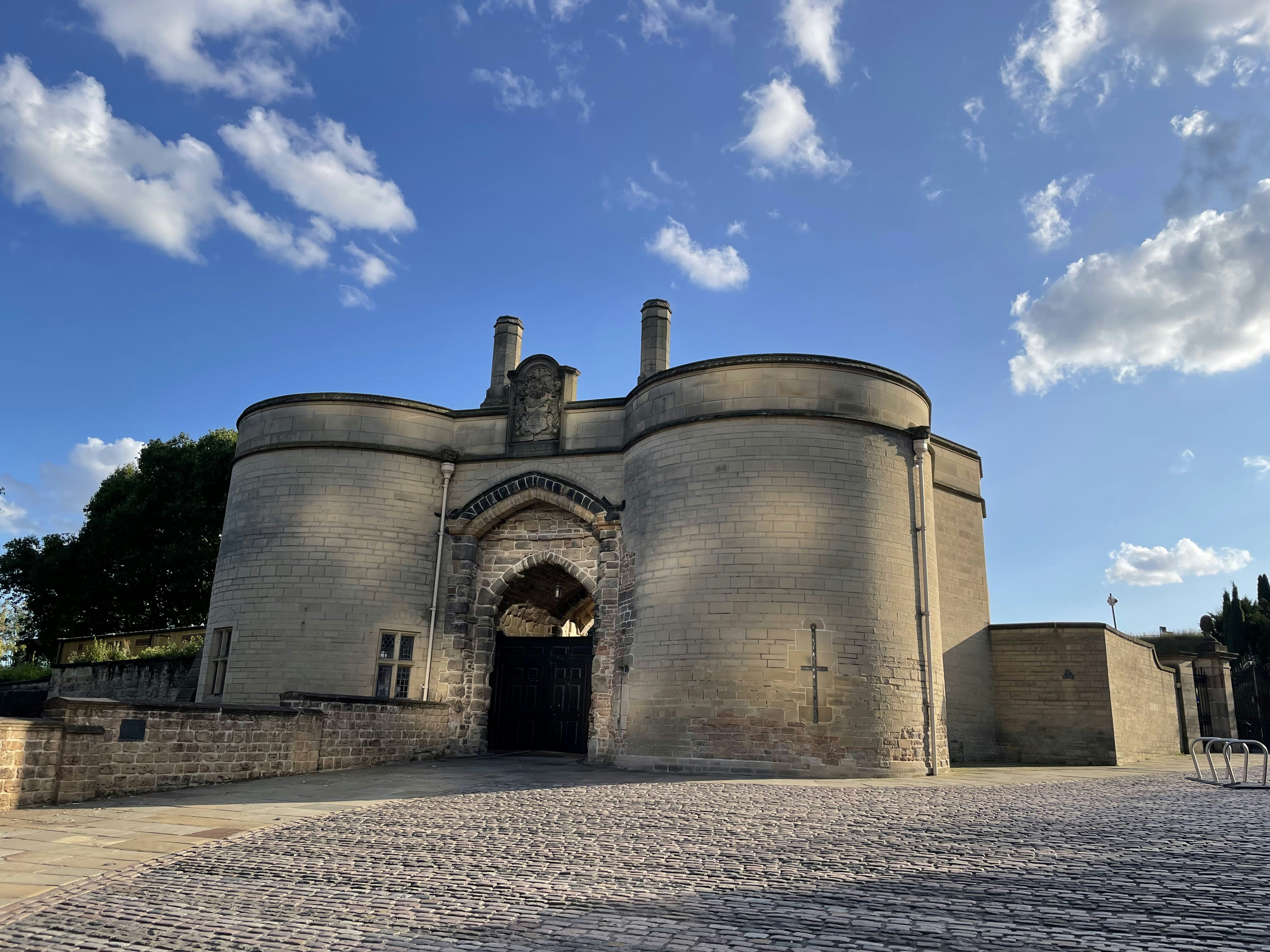 Historic stone fortress with cylindrical towers against a blue sky with scattered clouds.