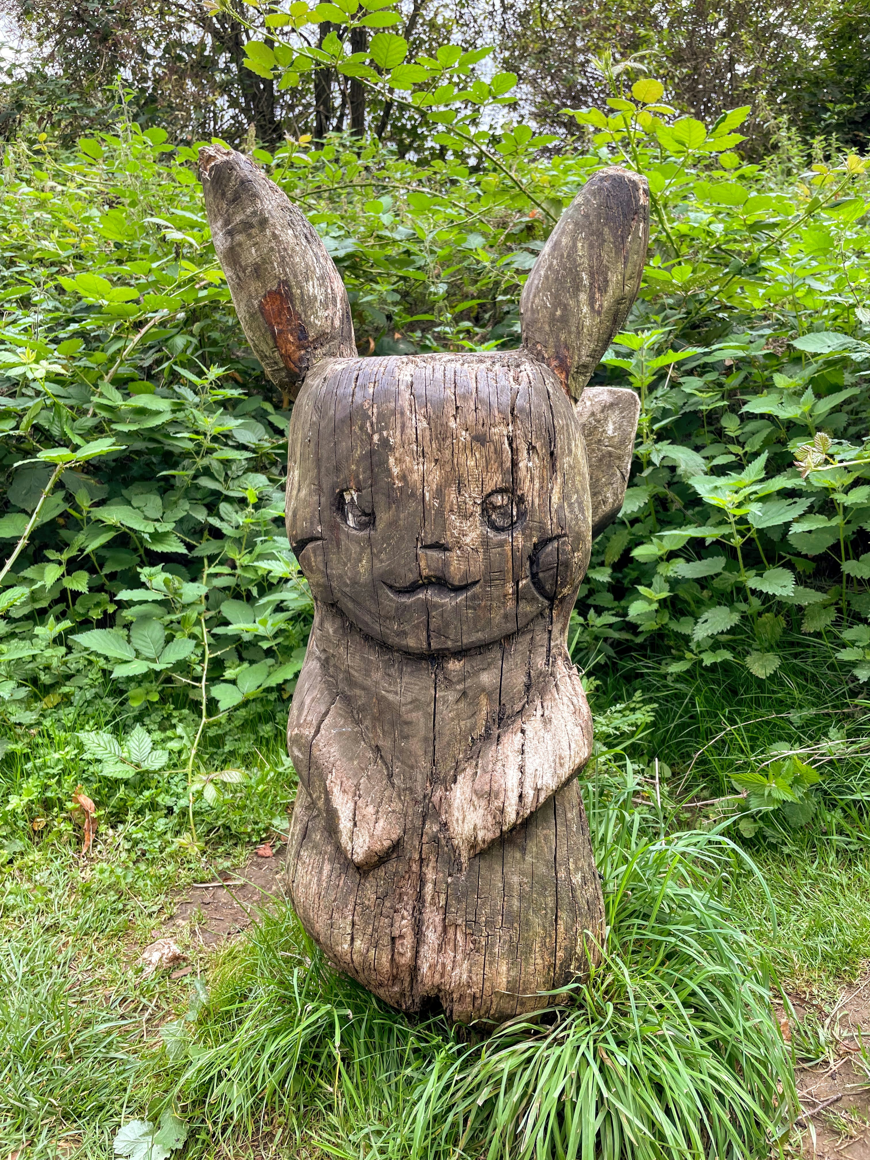 Smiling wooden rabbit guardian in a lush garden grove