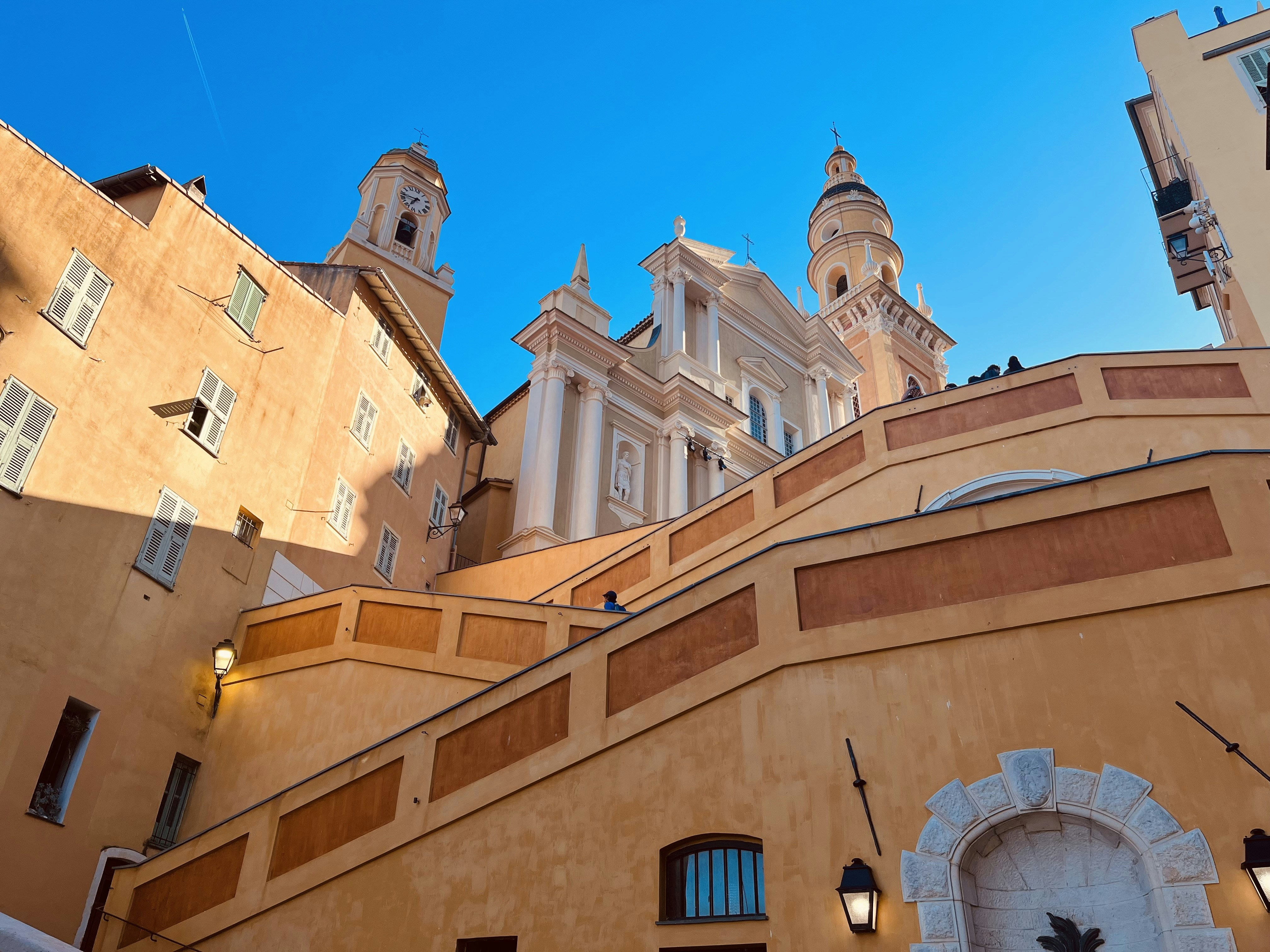 Historic architecture with warm-toned walls and ascending stairway under a vibrant blue sky.
