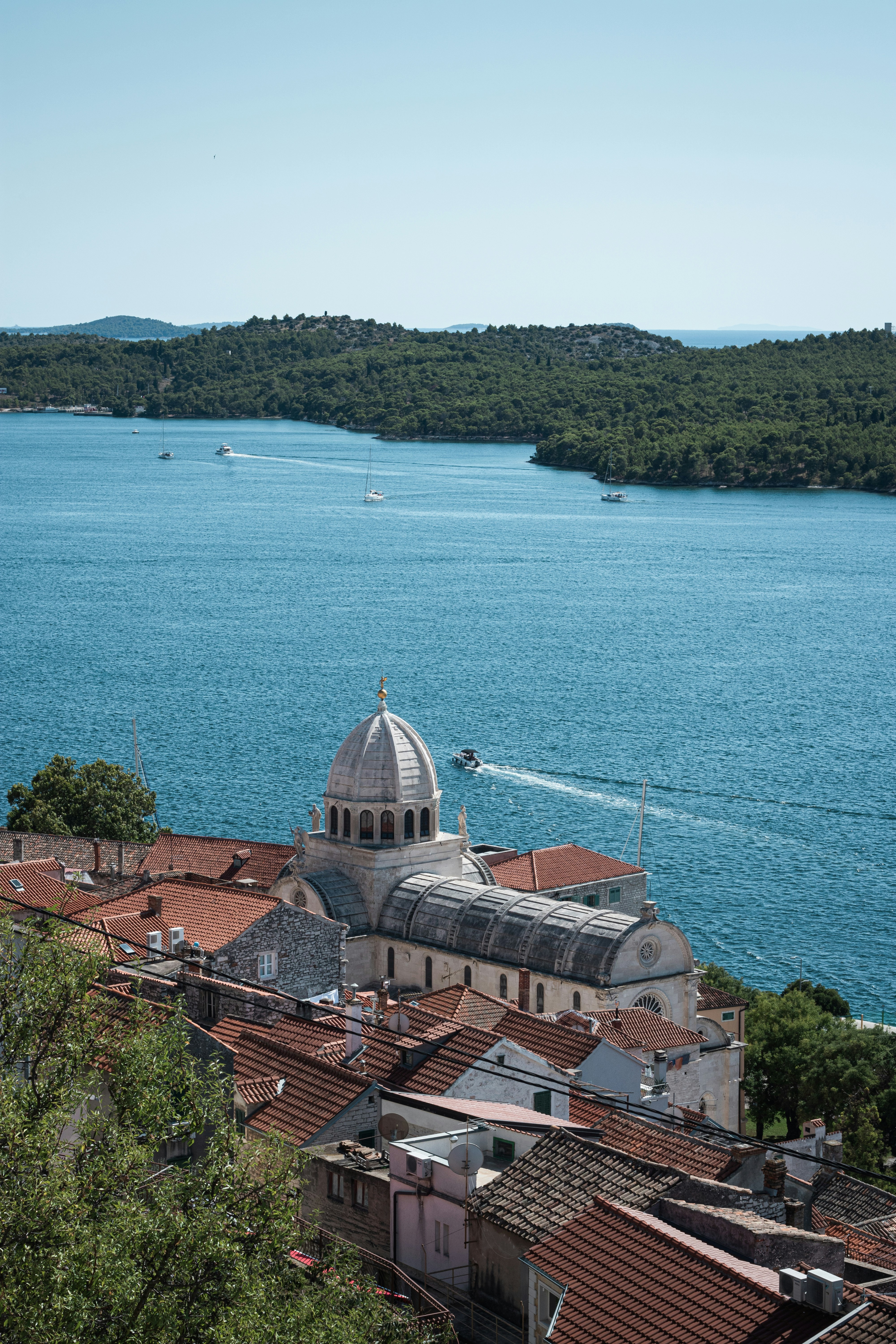 Domed Cathedral Rising Above Terracotta Rooftops by a Quiet Blue Bay