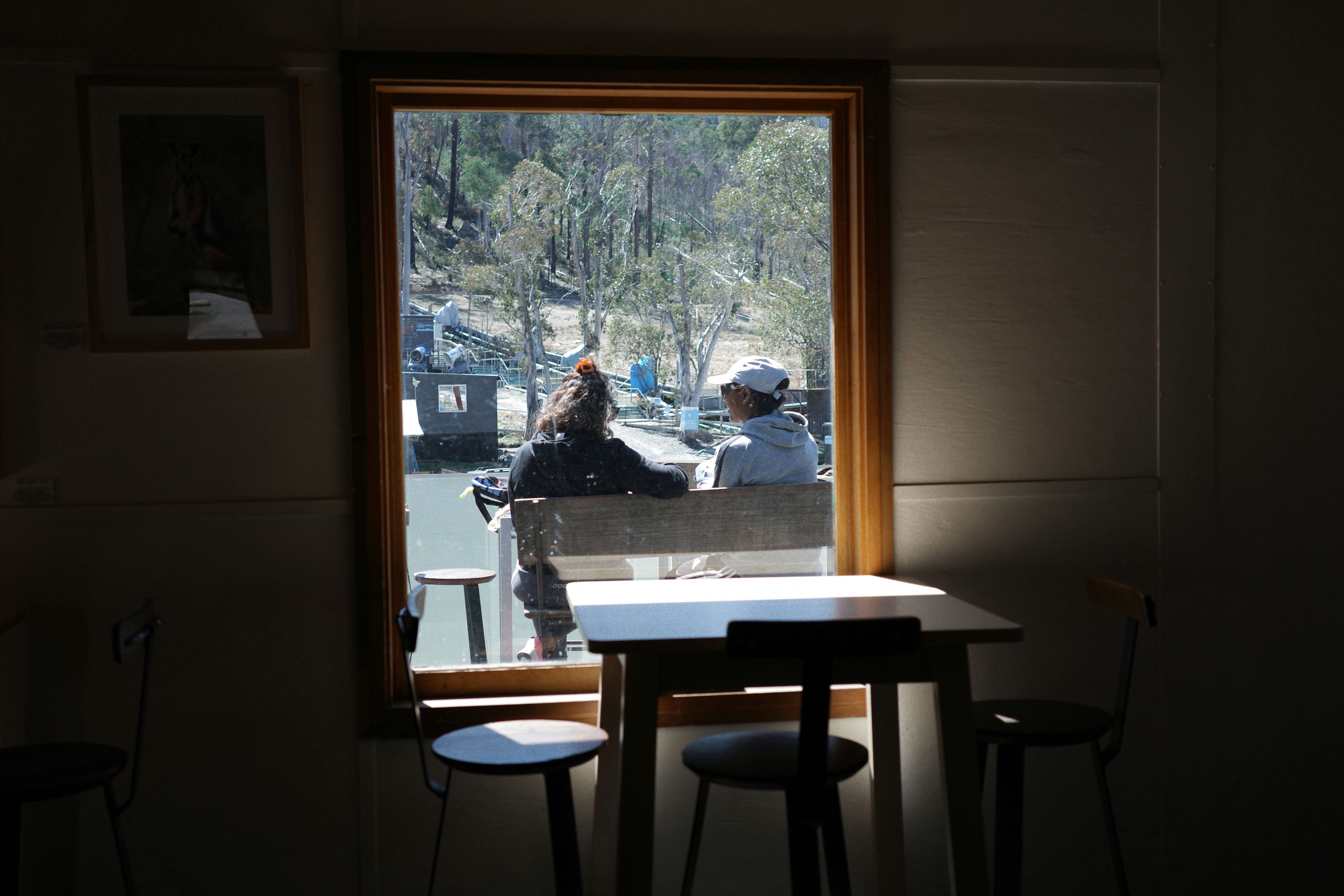 Windowed Bench: Two Figures Framed by Light in a Quiet Café