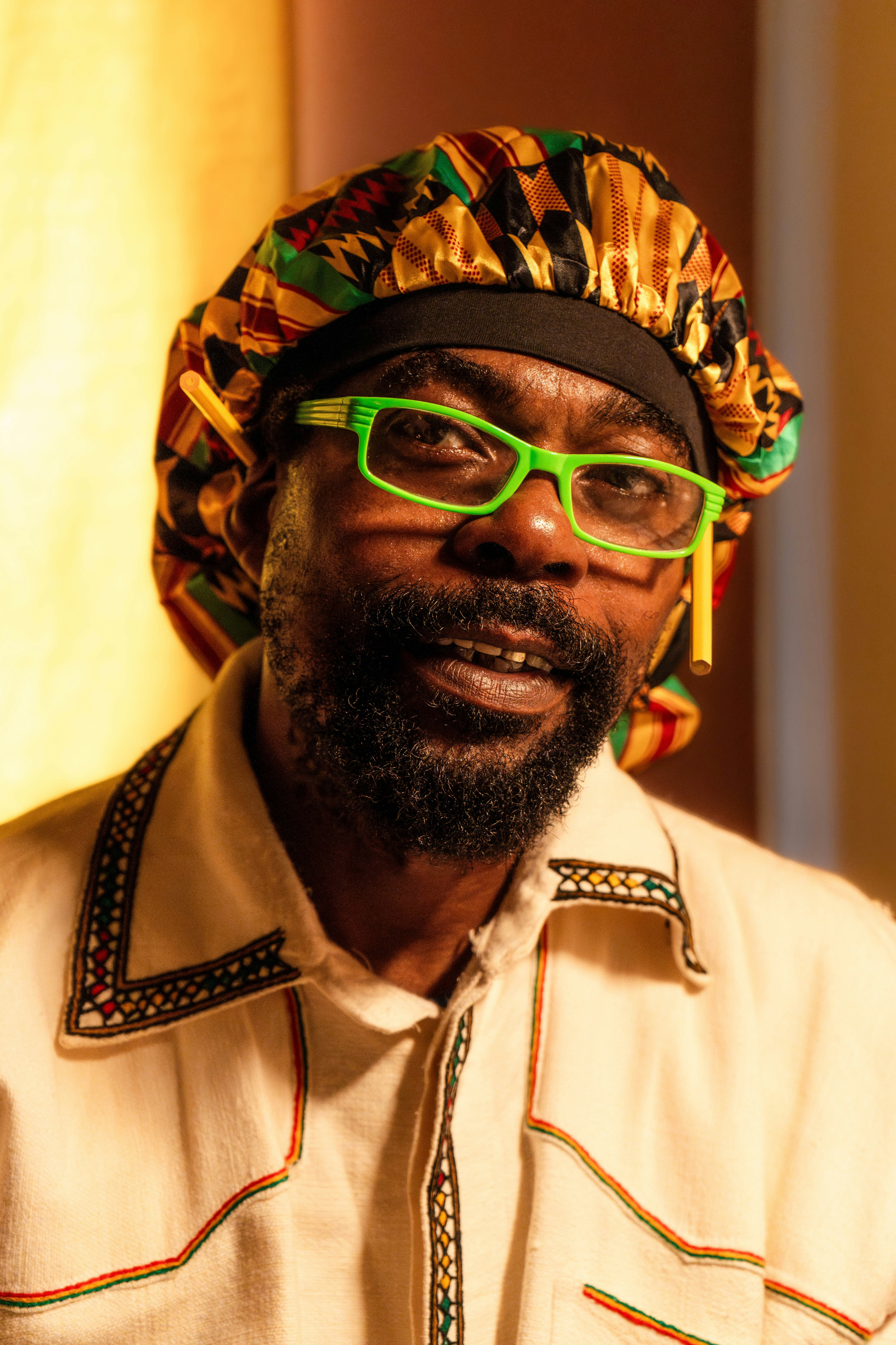 Neon-Green Glasses Meet Kente-Inspired Headwrap in Warm Portrait Light