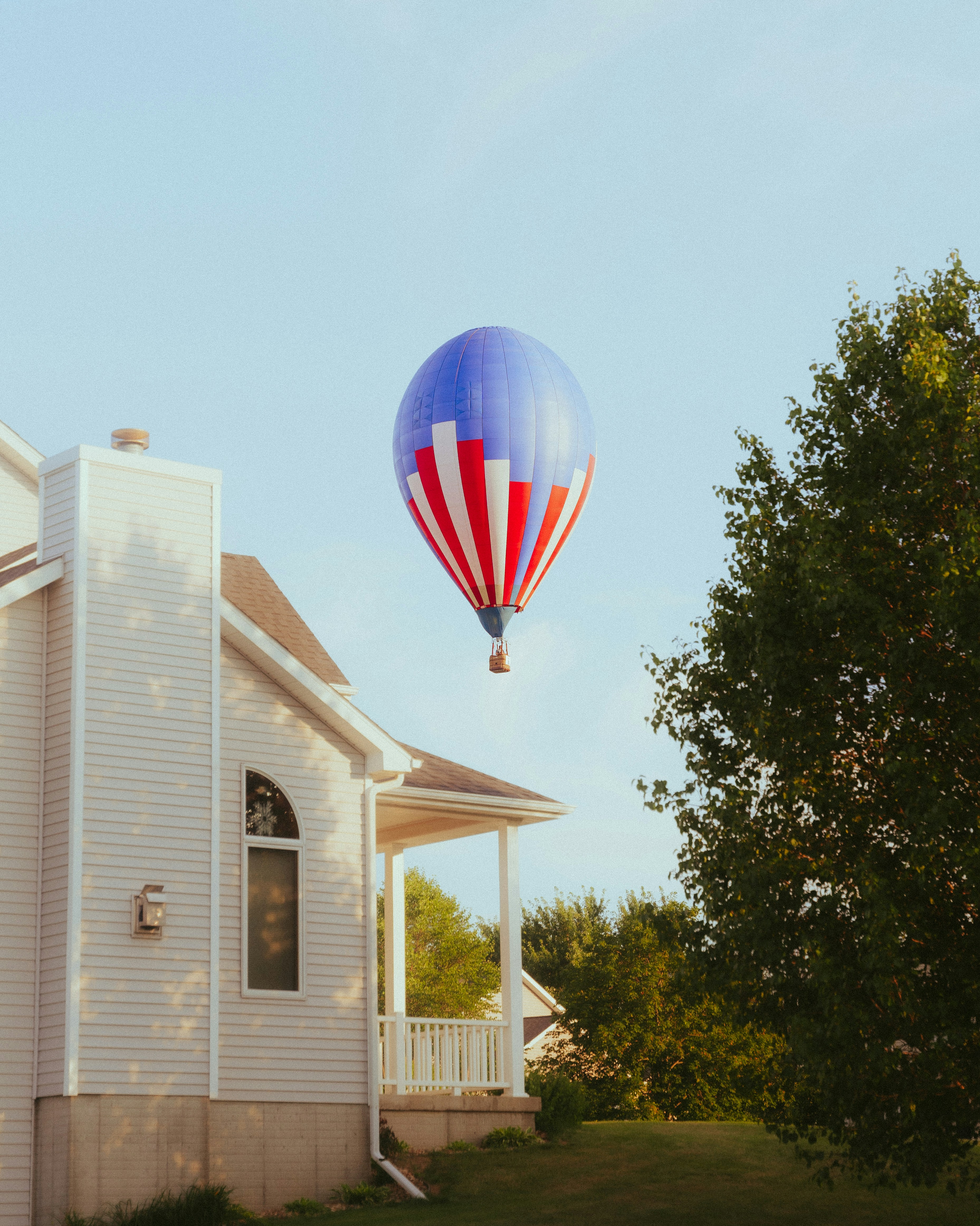 Blue Balloon Drifts Above a Quiet Suburban Porch