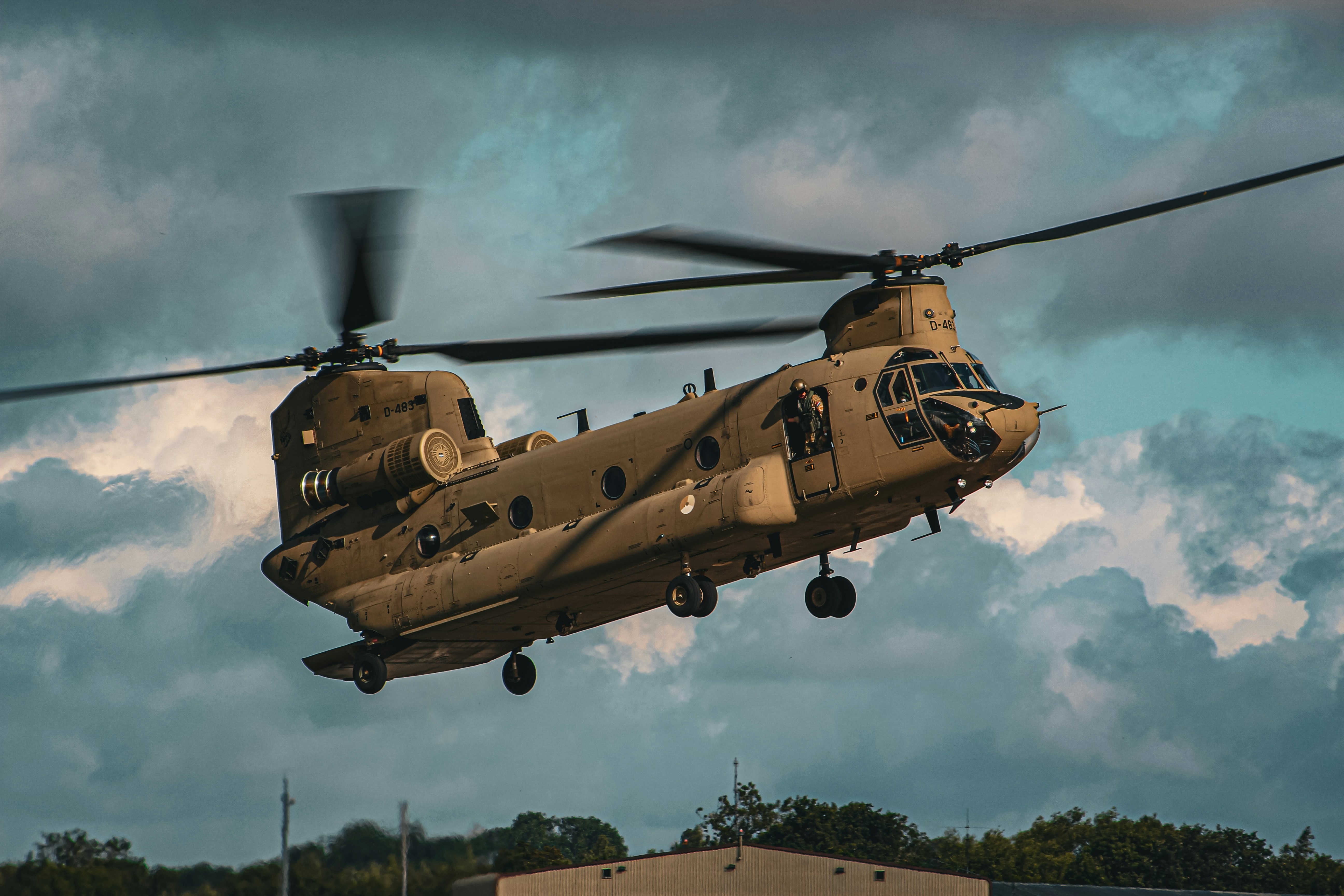 A large military helicopter flying through a cloudy sky photo – Free ...