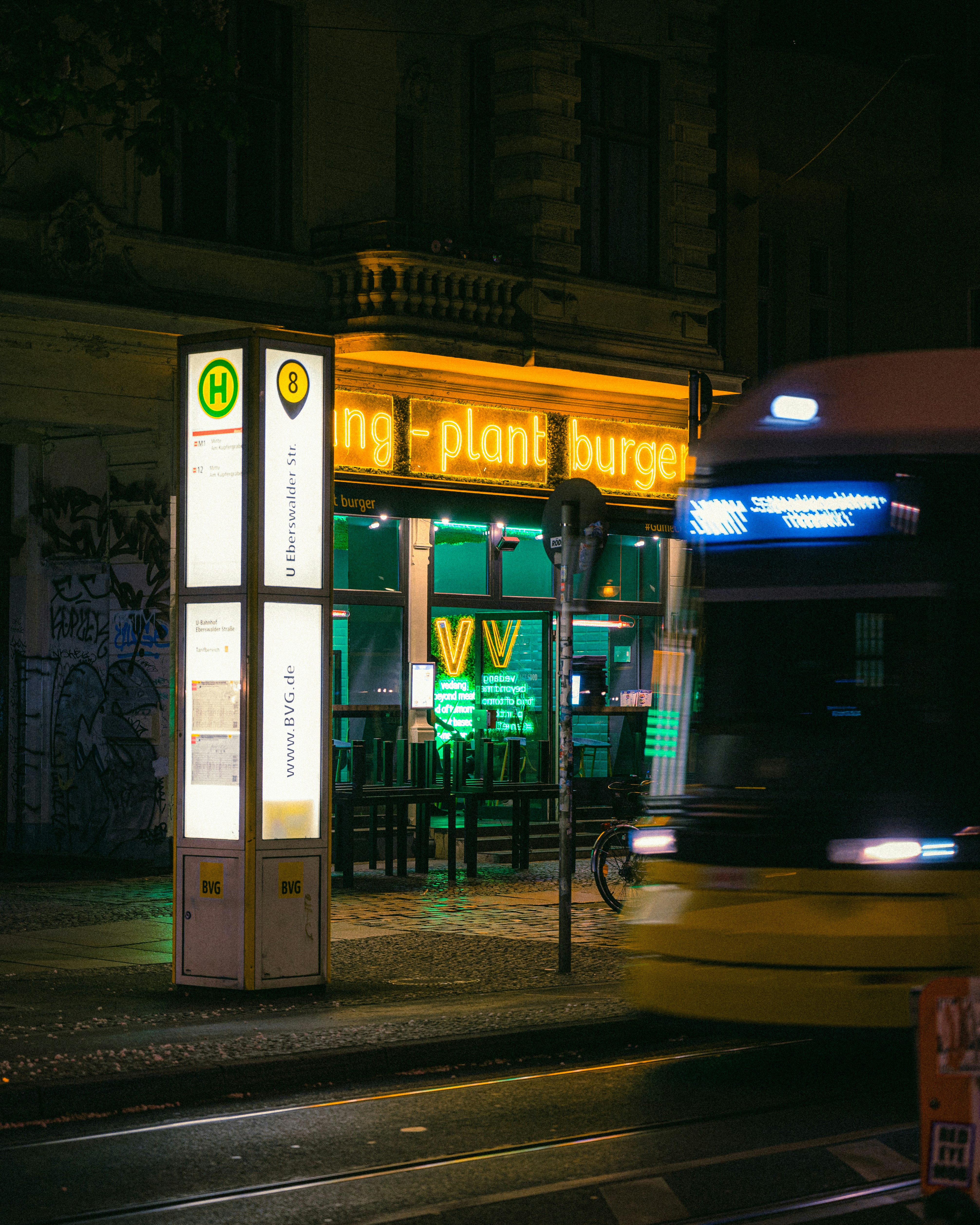 Neon Green in a Night Street: A Bus Surges Past a Burger Bar