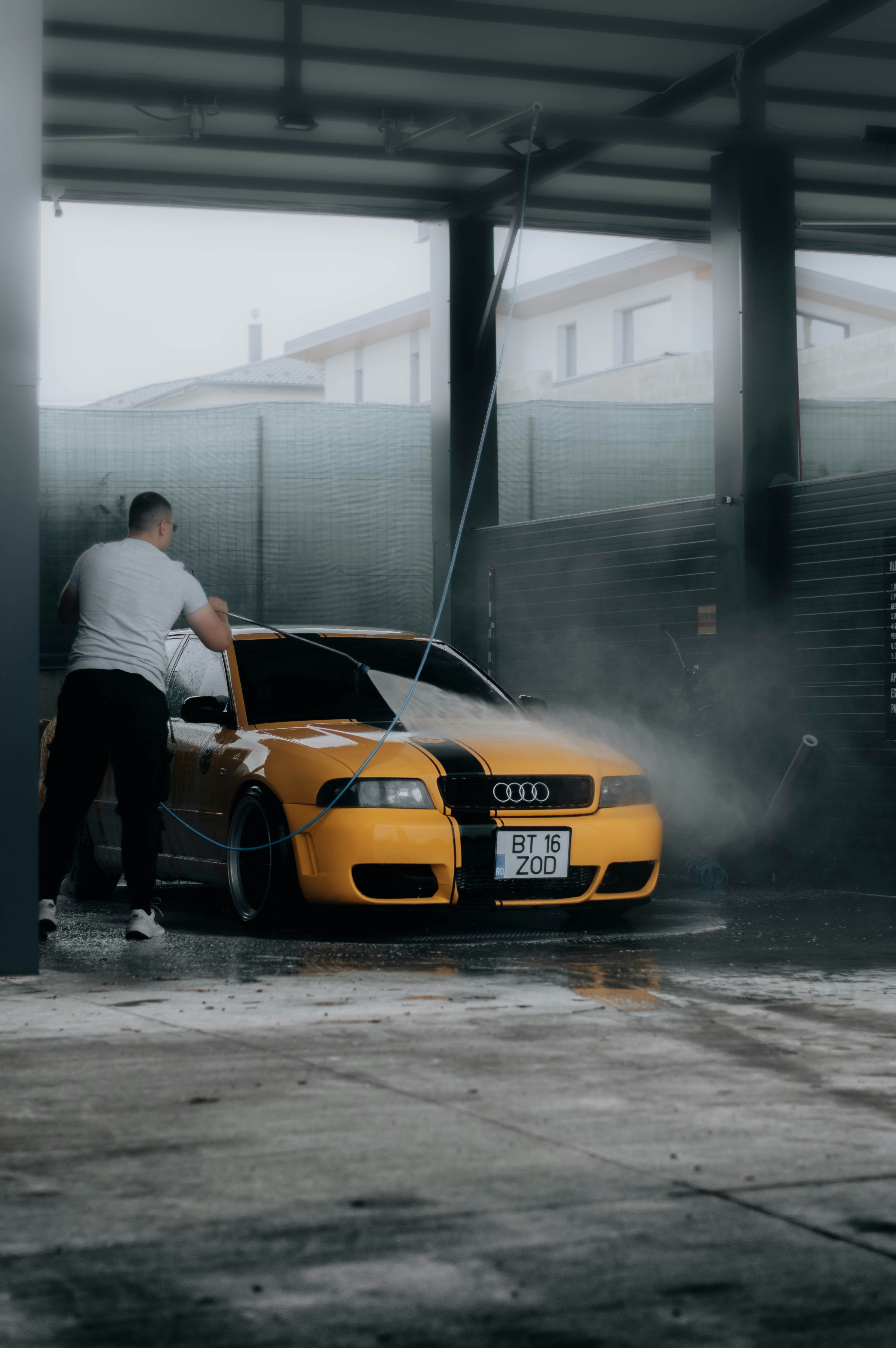 Yellow Audi Emerges from Steam: A Car-Wash Moment Under Industrial Beams