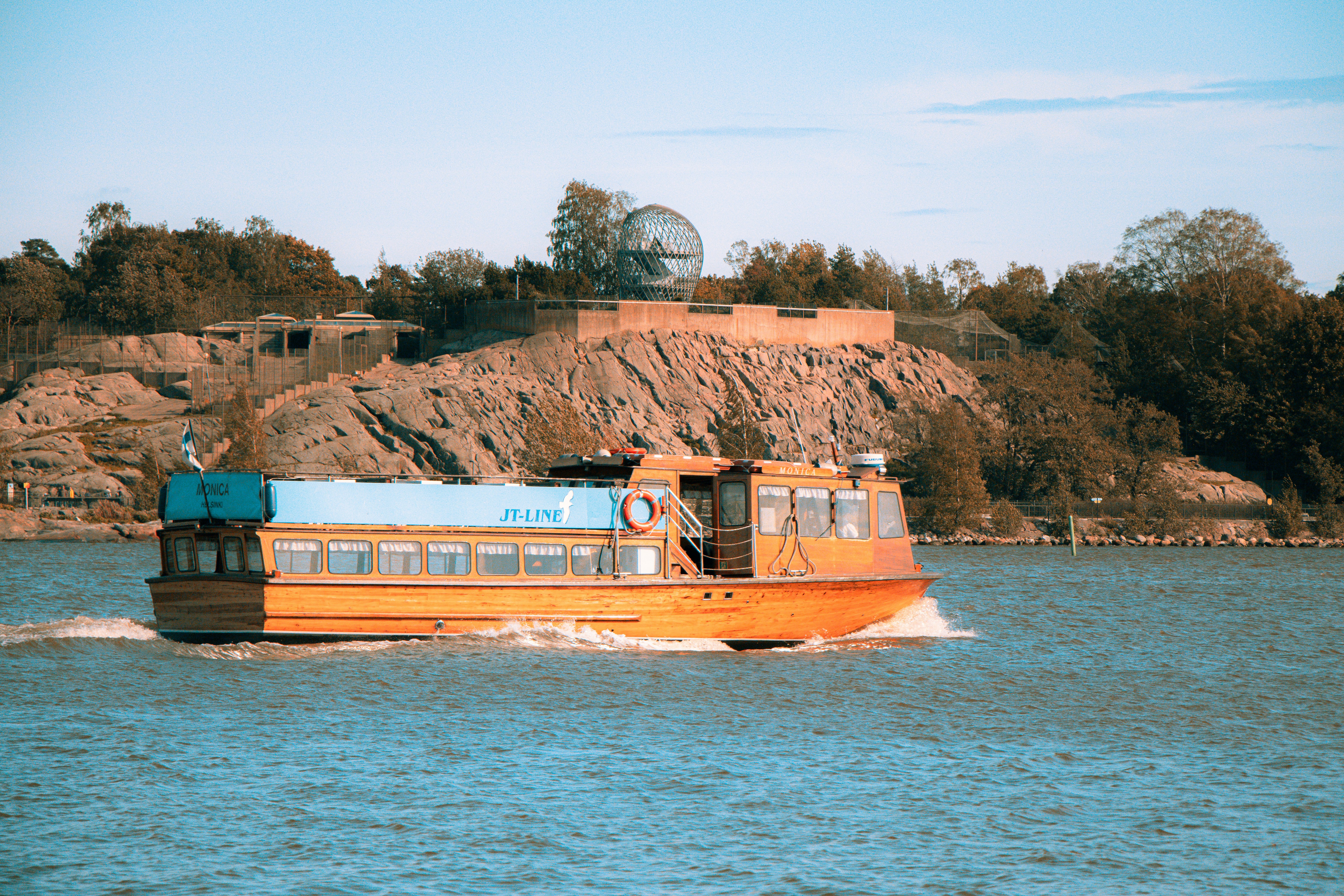 a boat traveling down a river next to a hill