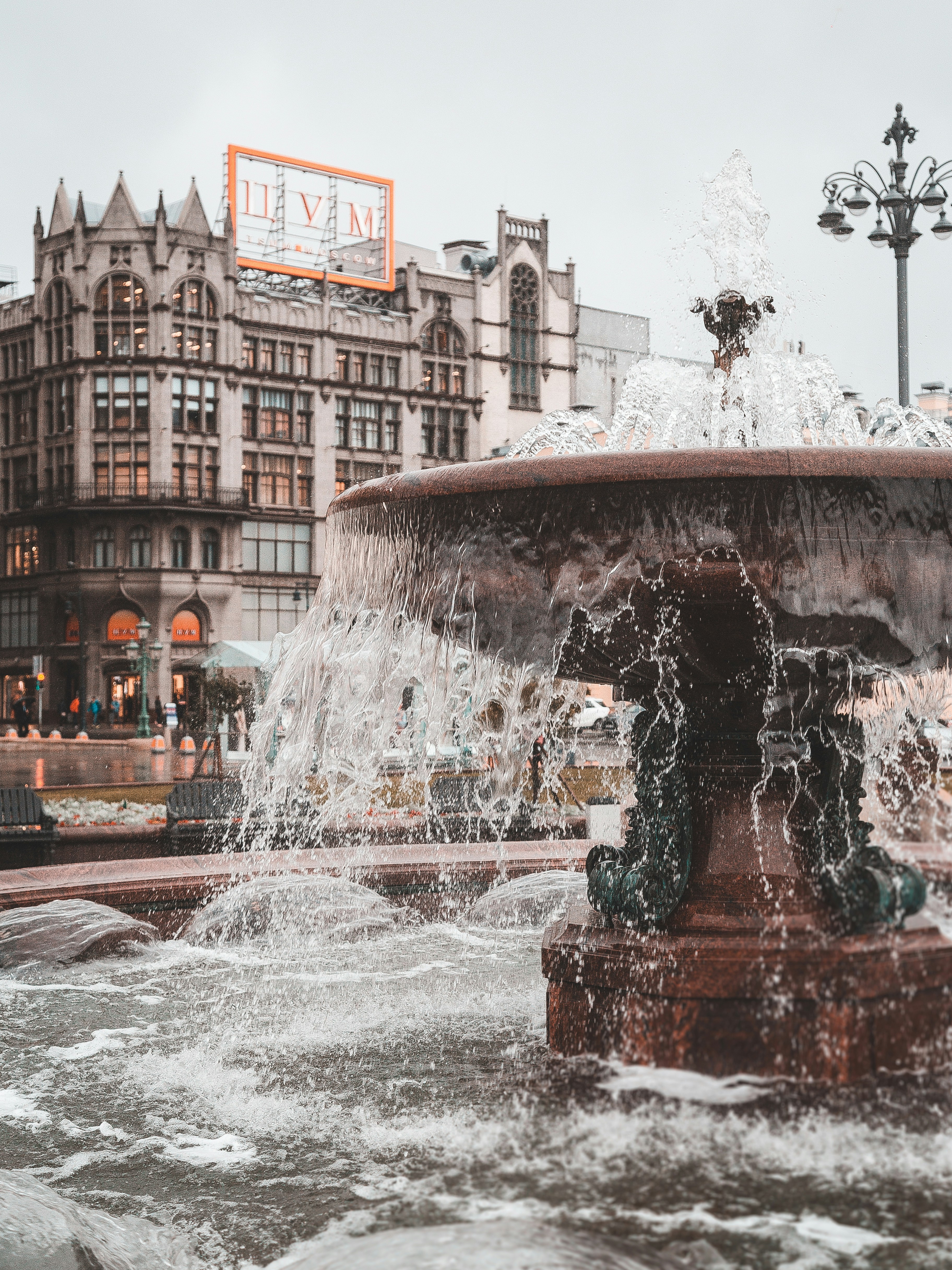 Cascade Script: City Fountain Framed by Neo-Gothic Facade and Neon Sign