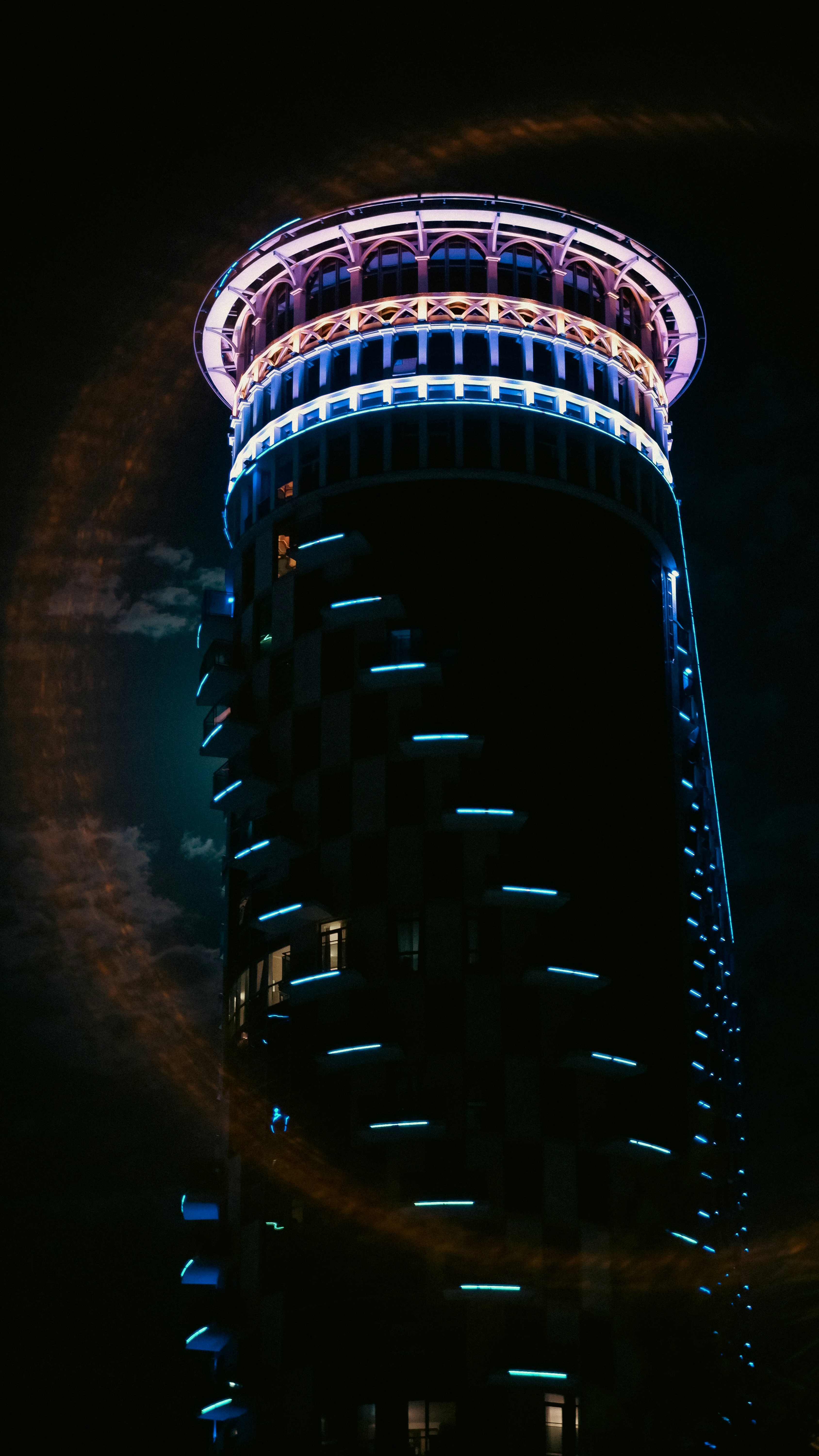 Neon Halo Crown: Nighttime Spiral of Light Around a Circular-Topped Tower