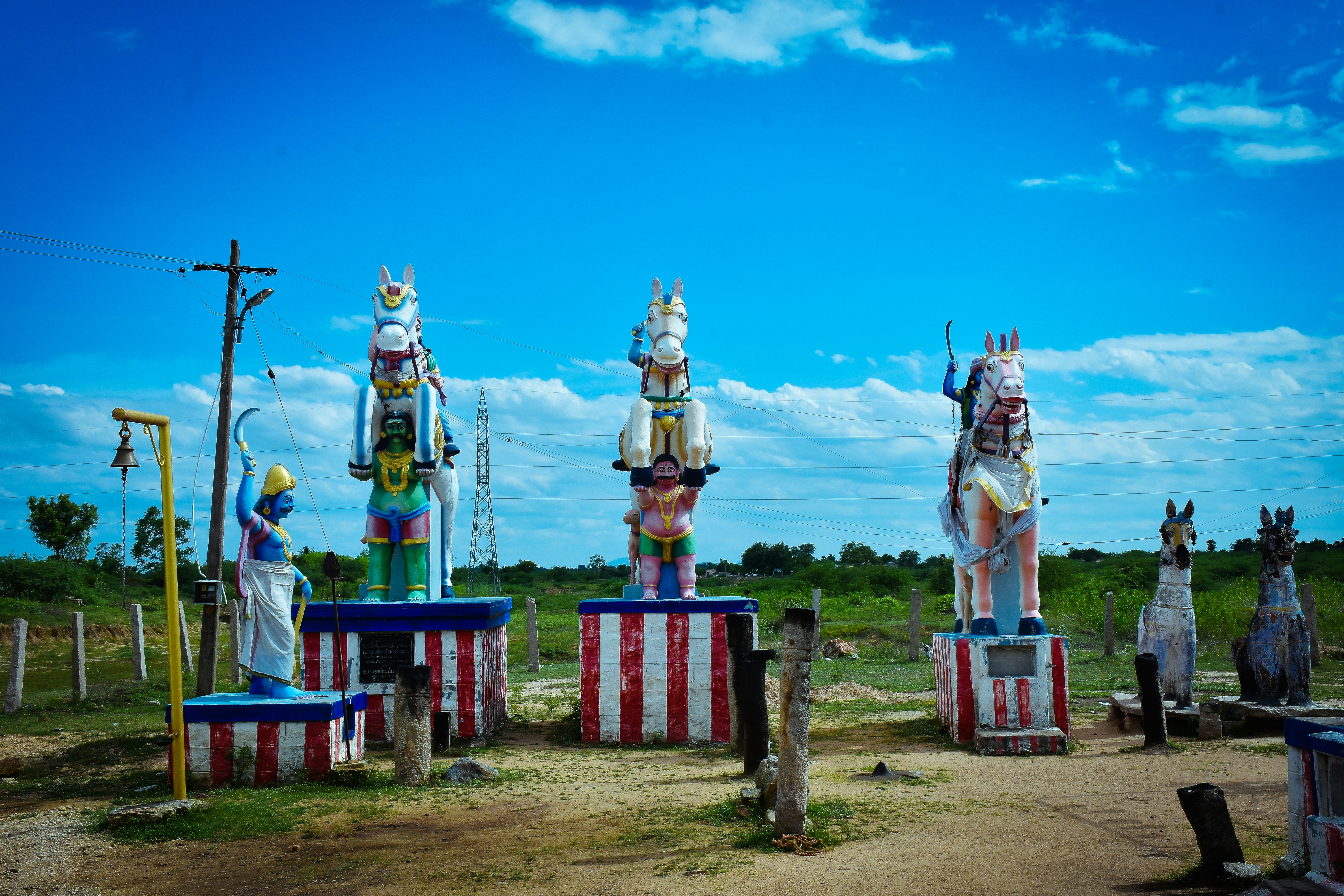 A group of statues sitting on top of a dirt field photo – Free Travel ...