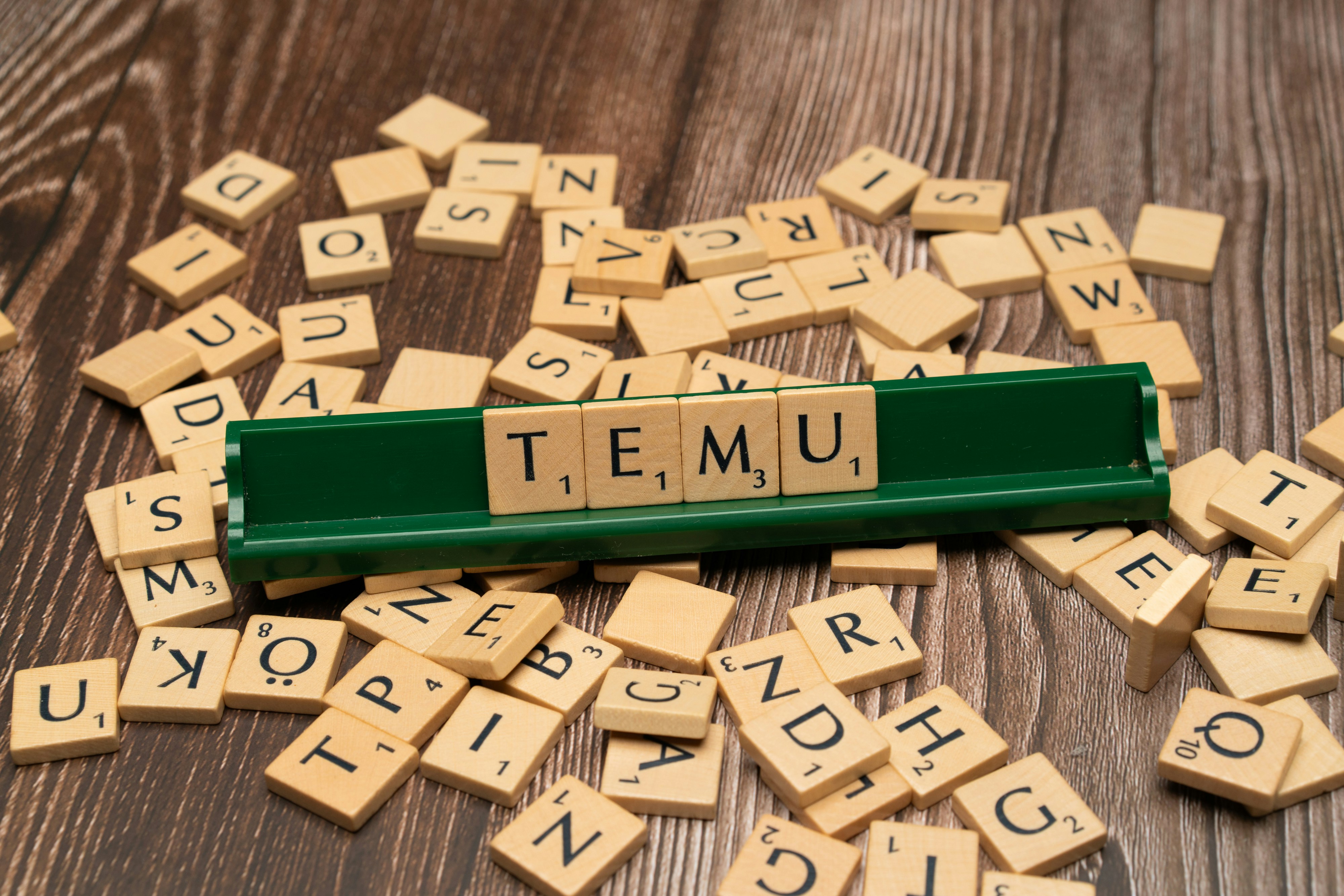 Scrabble tiles spelling the word temu on a wooden surface photo – Free ...