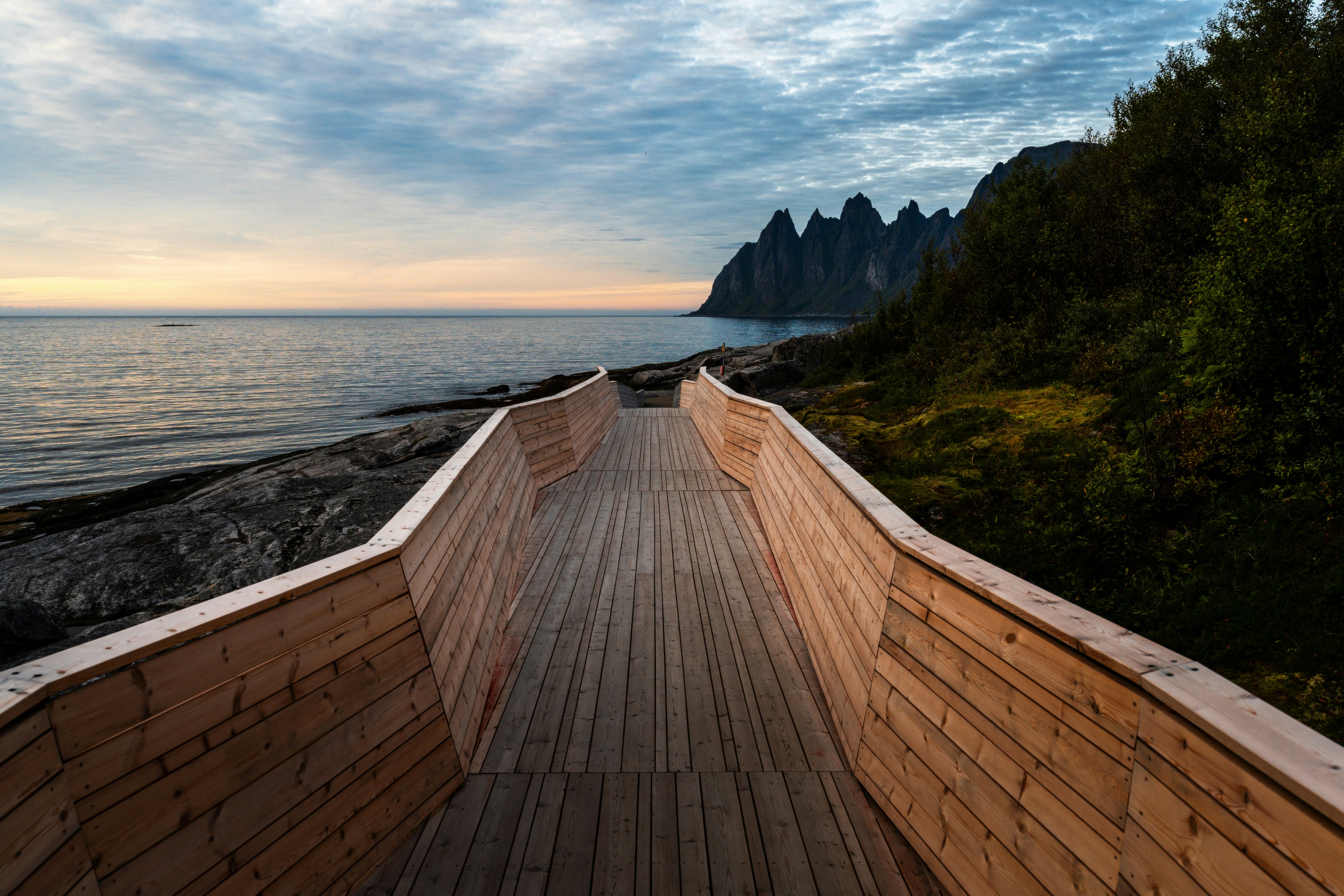 Sunset Boardwalk Toward Rugged Cliffs and a Quiet Sea