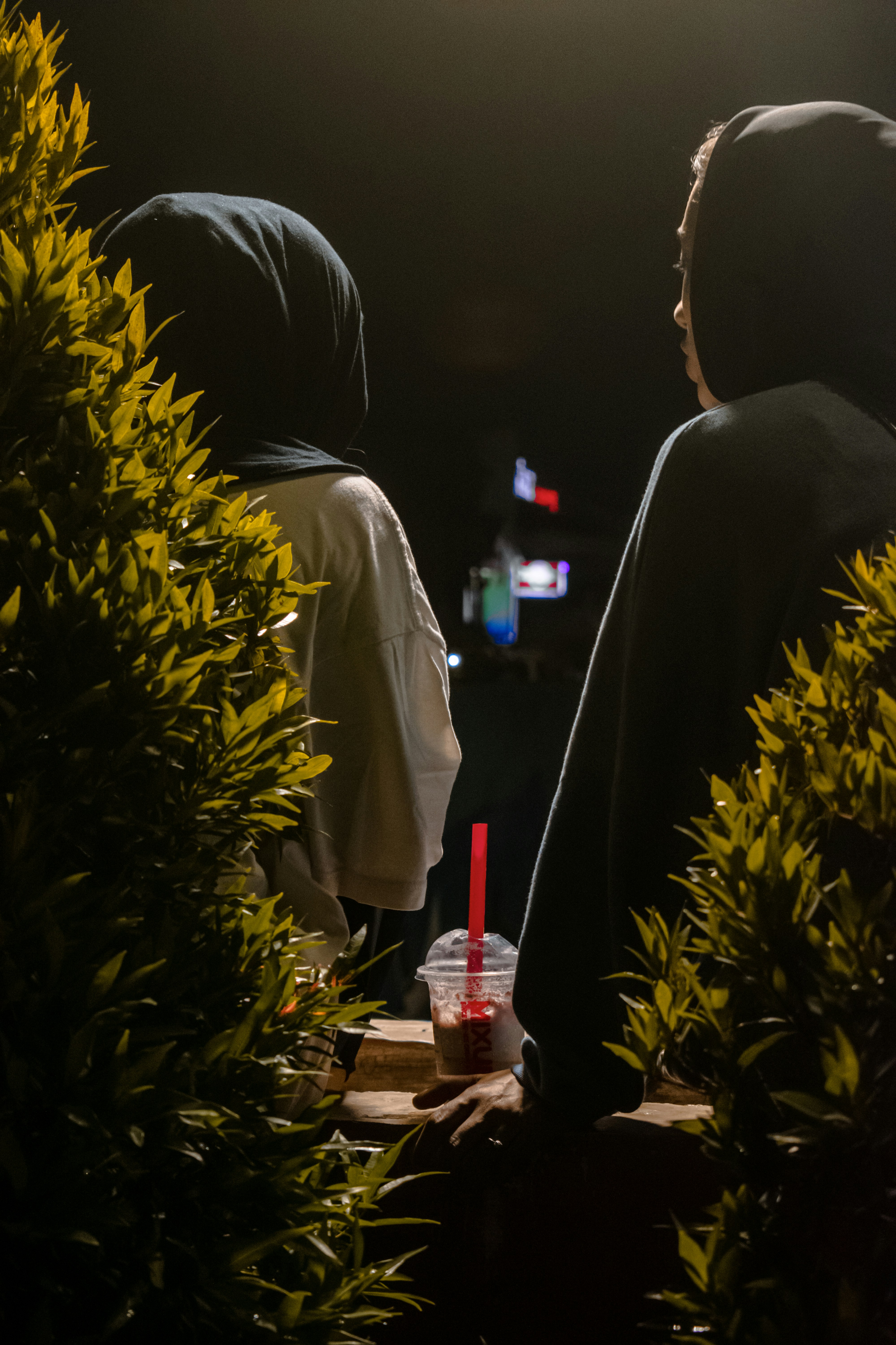 Hooded Figures in Night Drive-Through Glow