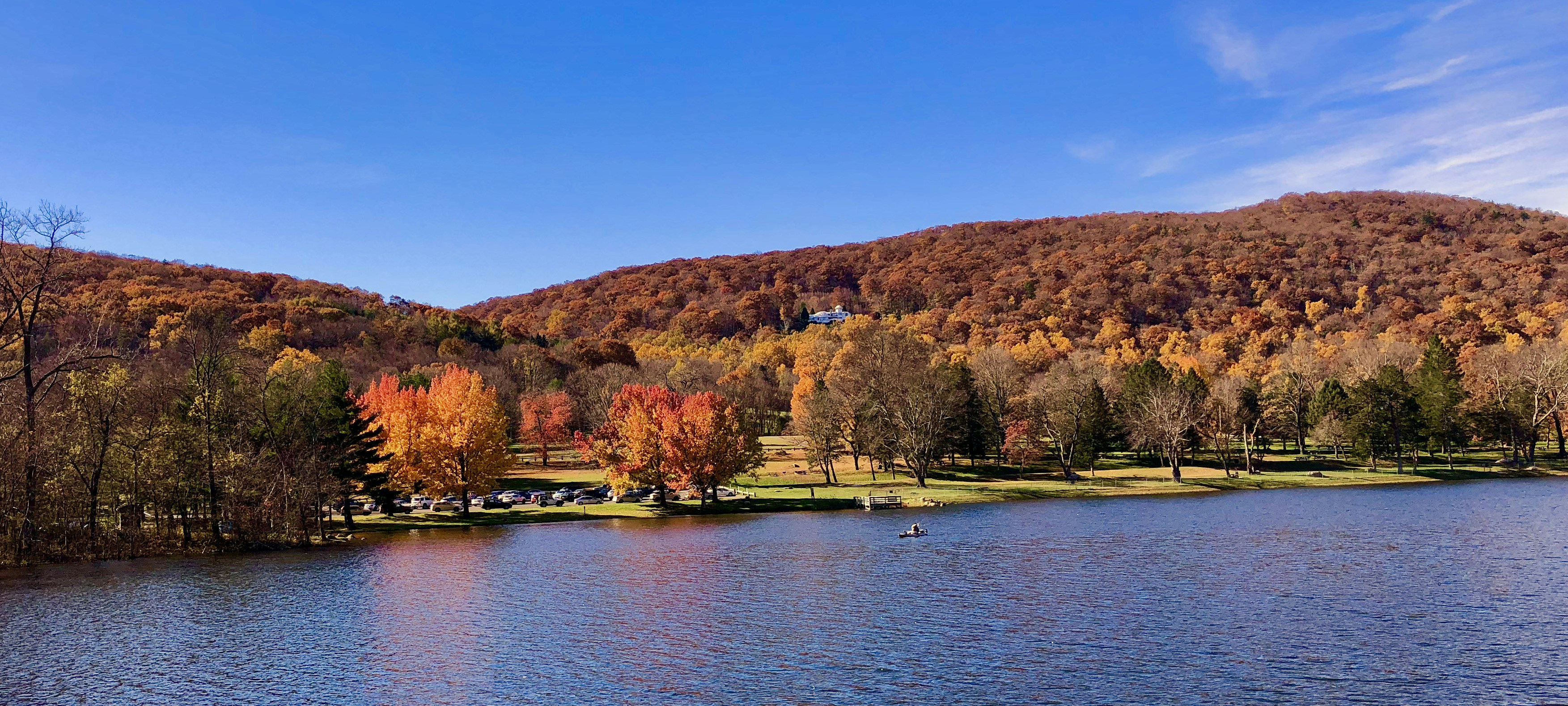 Vibrant fall foliage surrounds a tranquil lake under a clear blue sky.