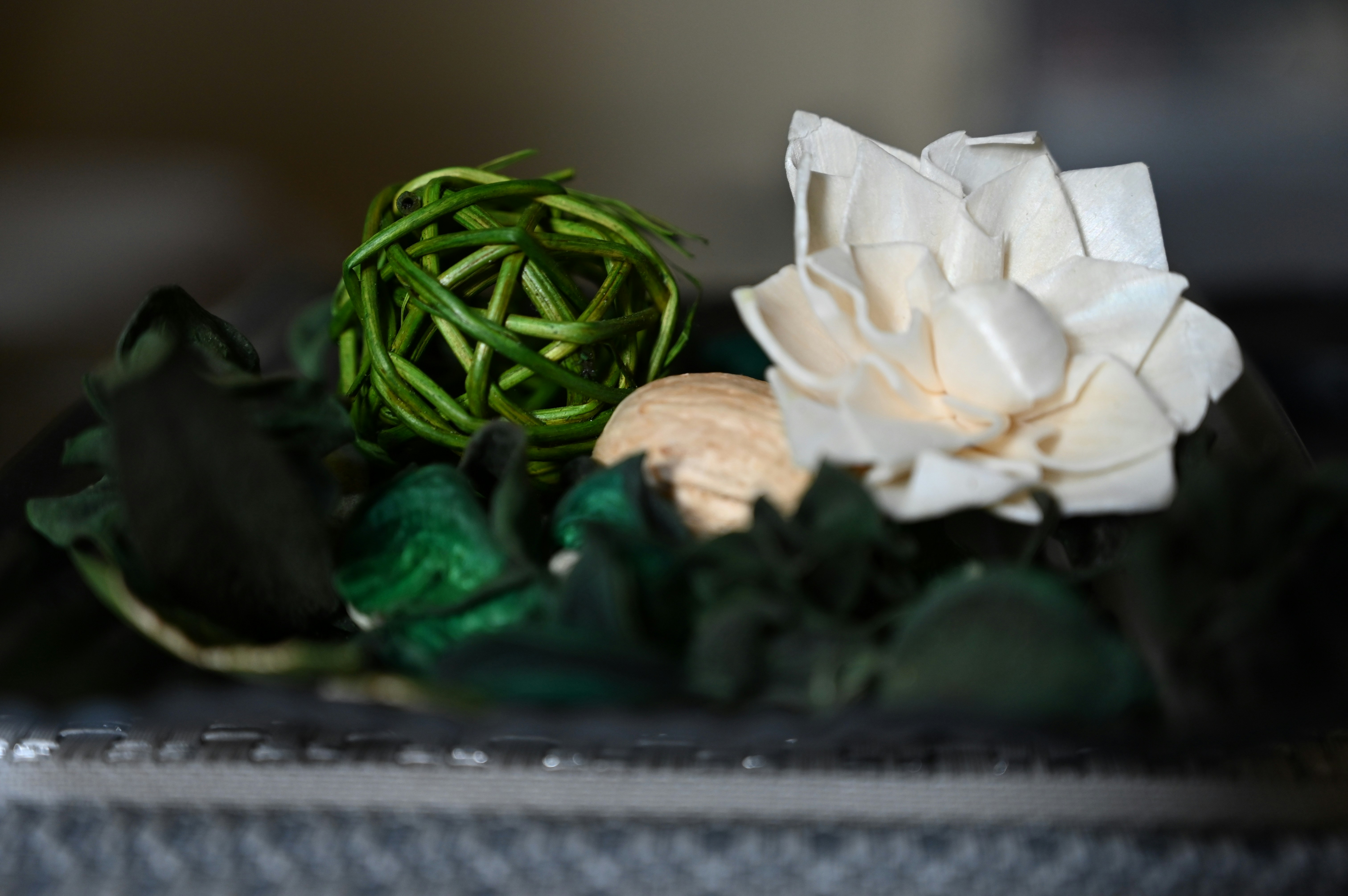 Green woven orb beside a pale blossom on a velvet stage
