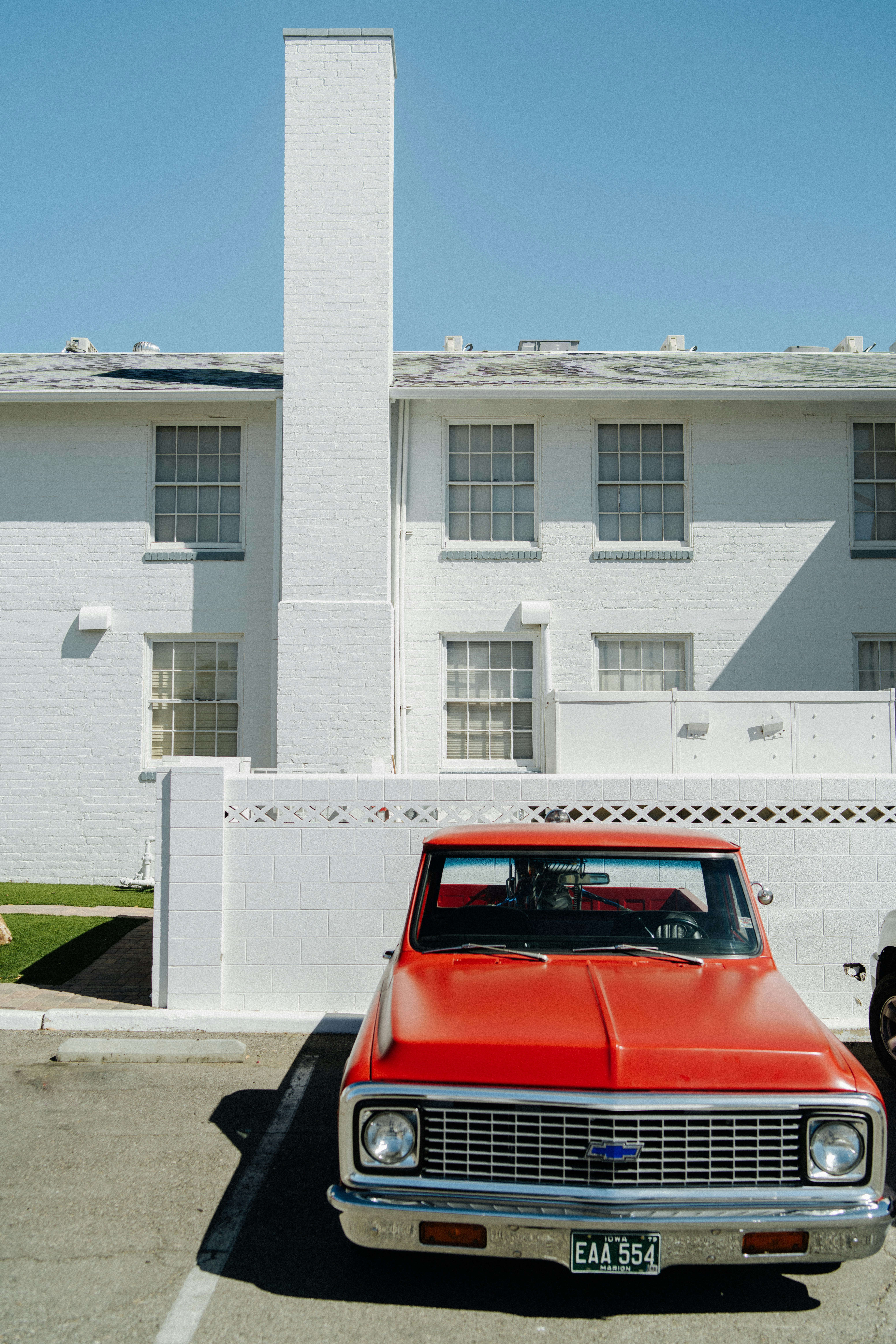 Red Pickup Under a White Hotel: A Quiet Street Snapshot