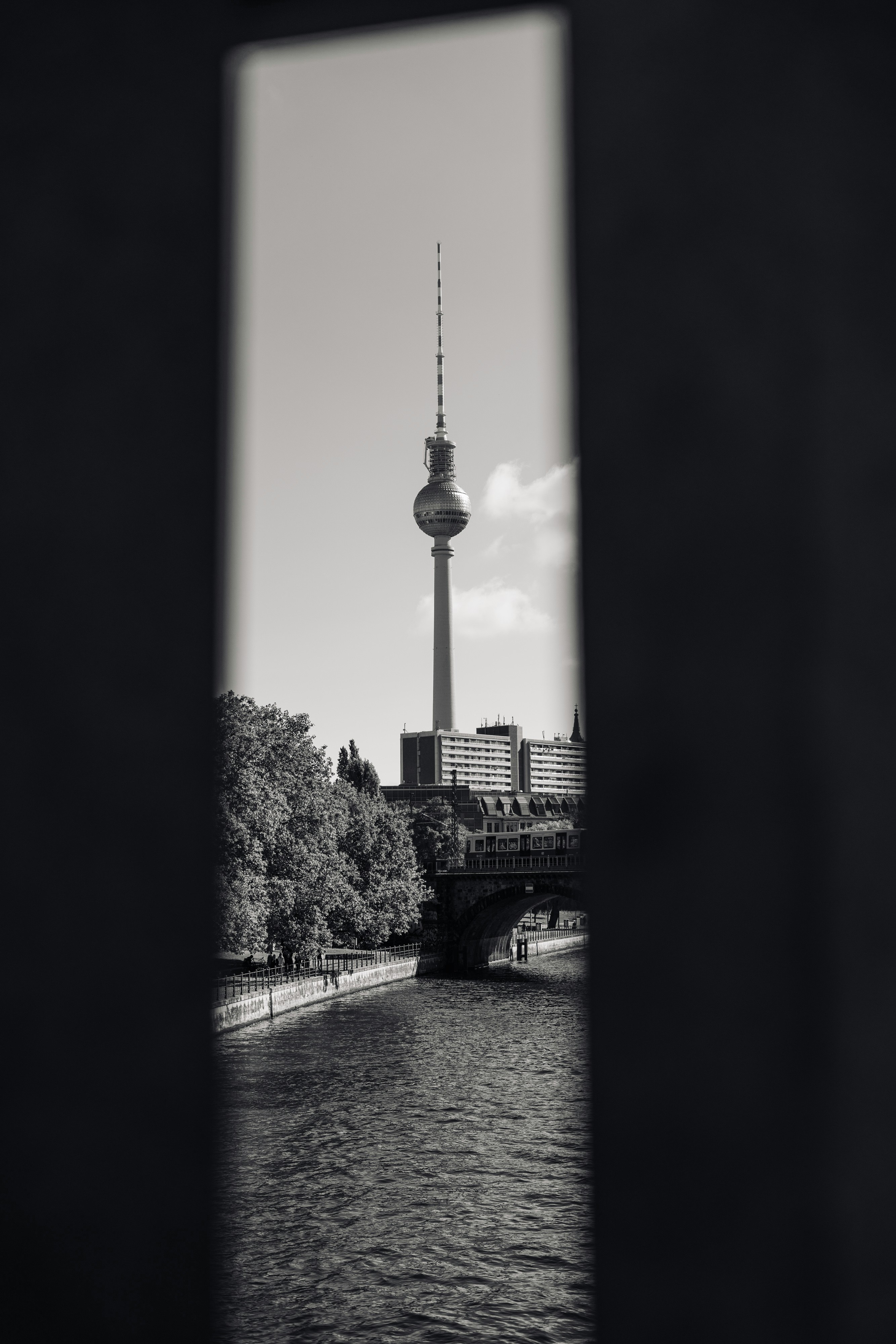 a black and white photo of a river with a tower in the background