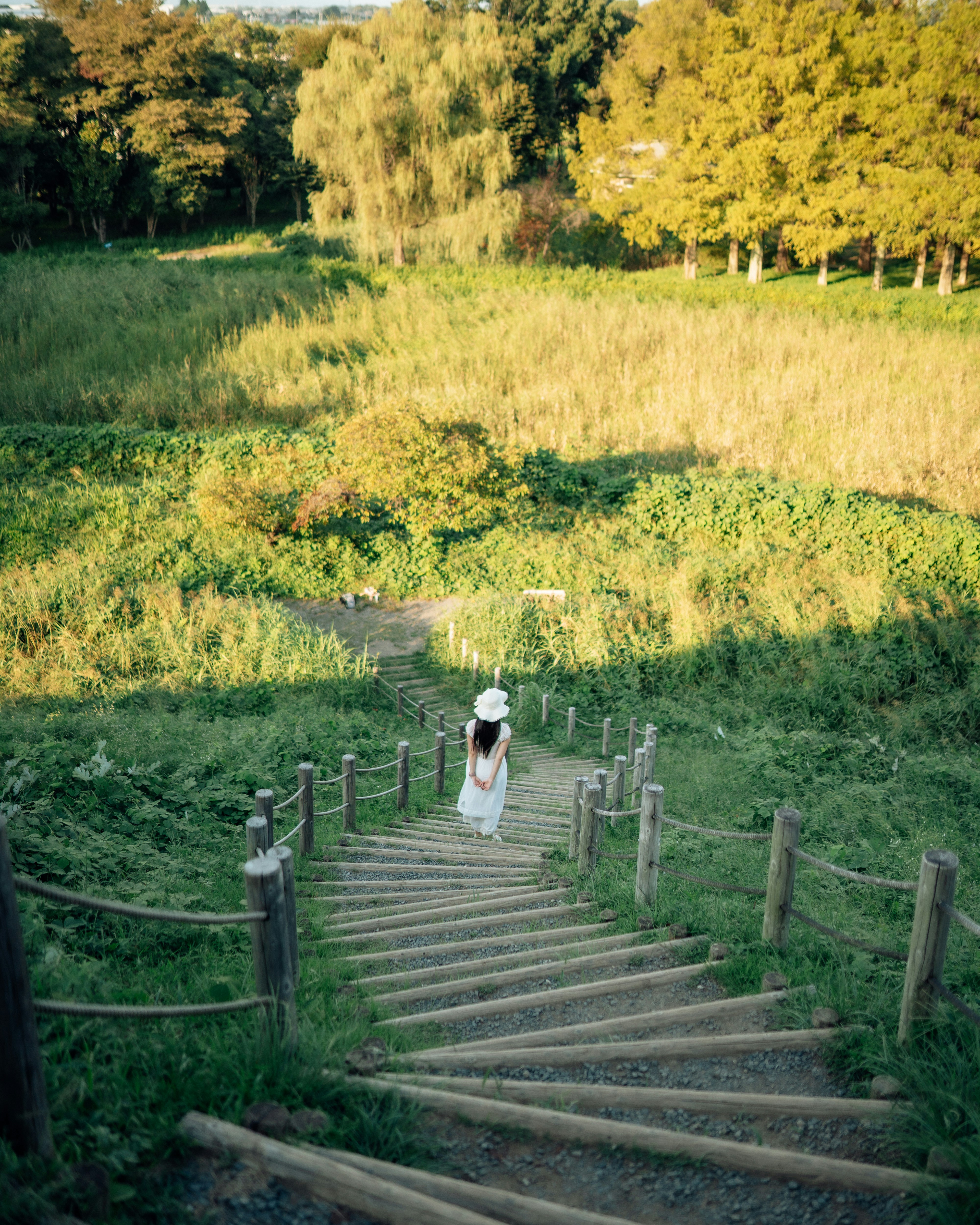 Golden Hour Descent: A Woman in White on a Rustic Staircase
