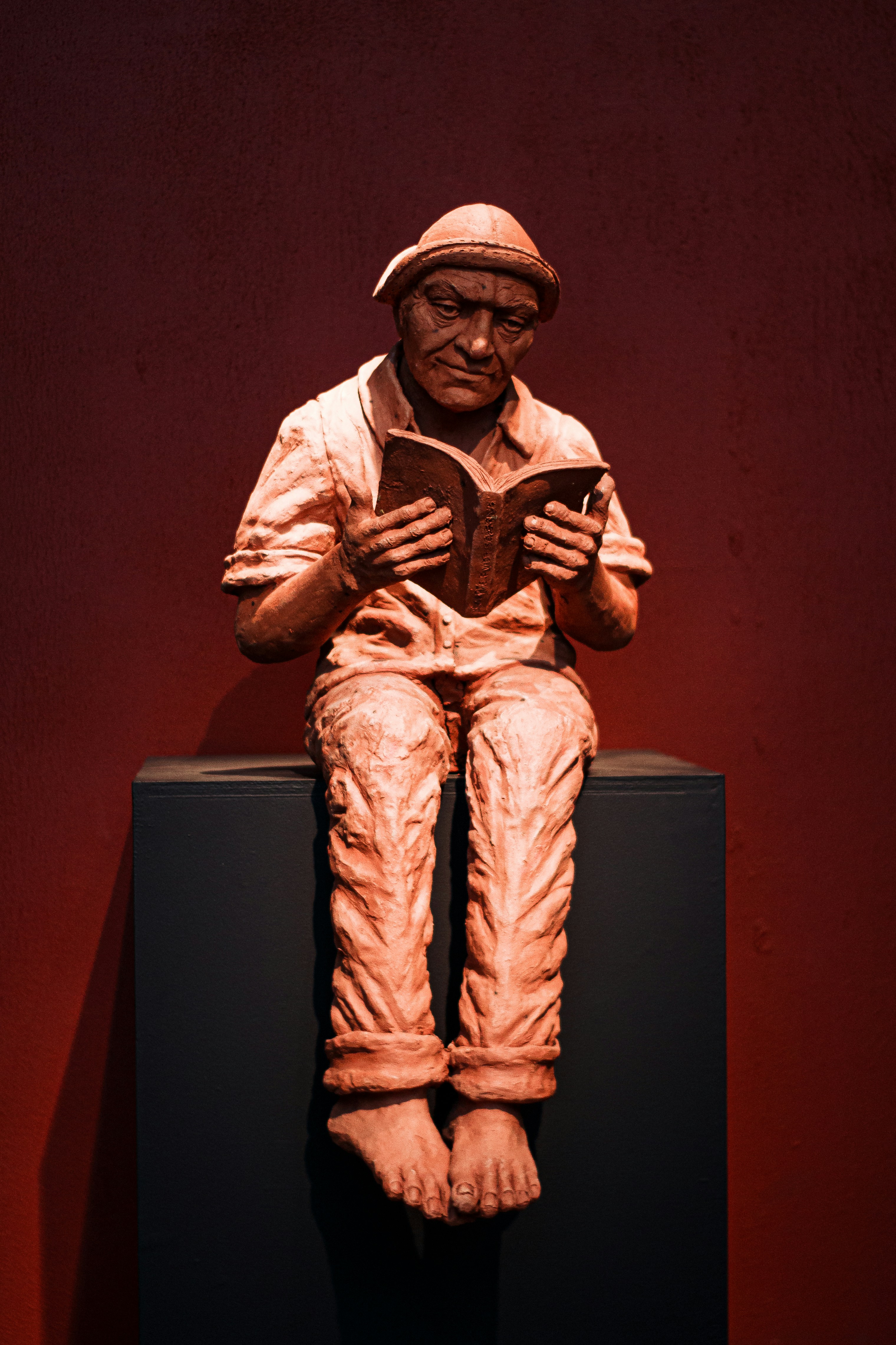Terracotta Reader Under a Crimson Spotlight