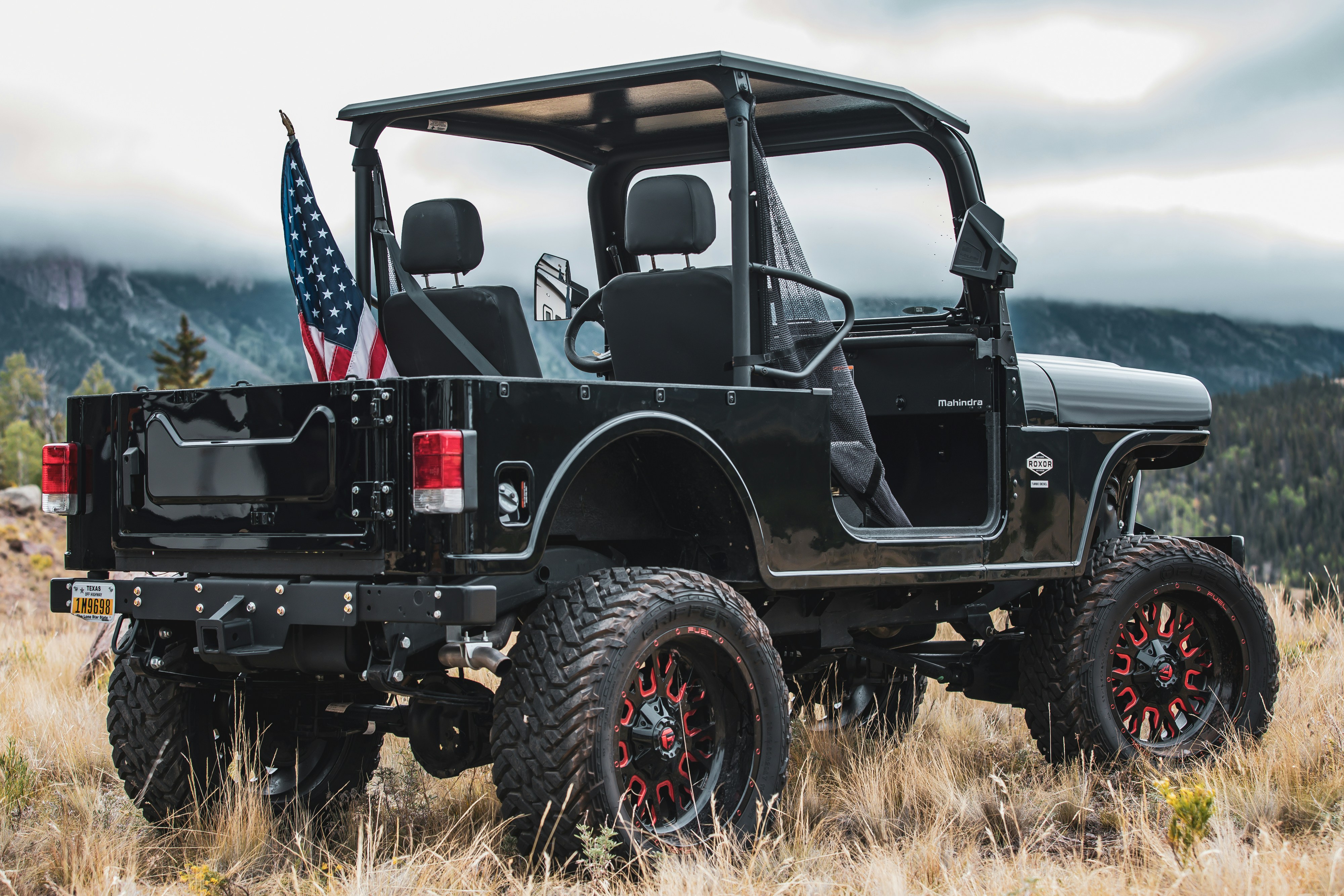 Midnight Cruiser: A Vintage Jeep Anchored in a Windswept Field Against a Mountain Backdrop