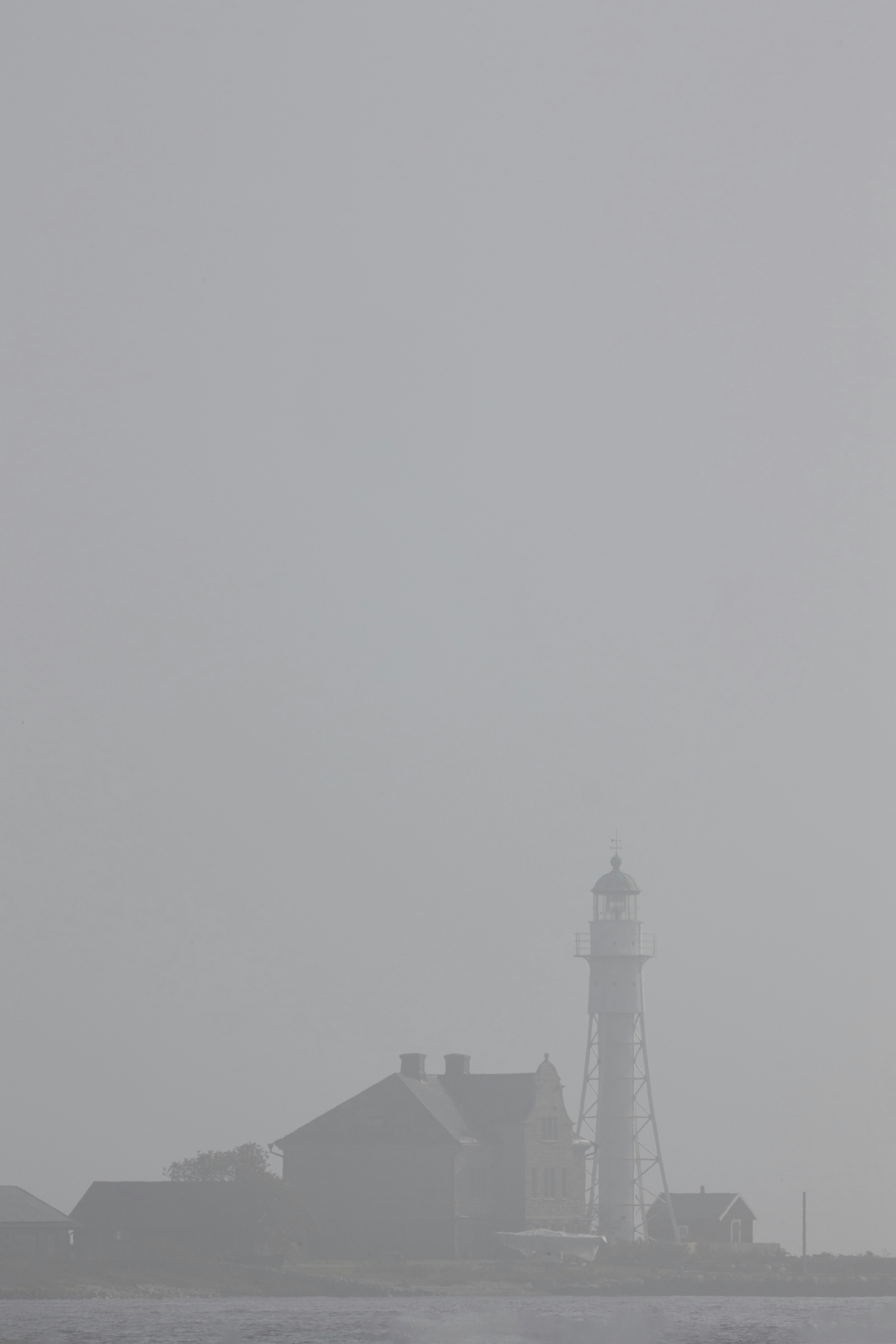 Fogbound Beacon: Distant Lighthouse Standing Against the Mist
